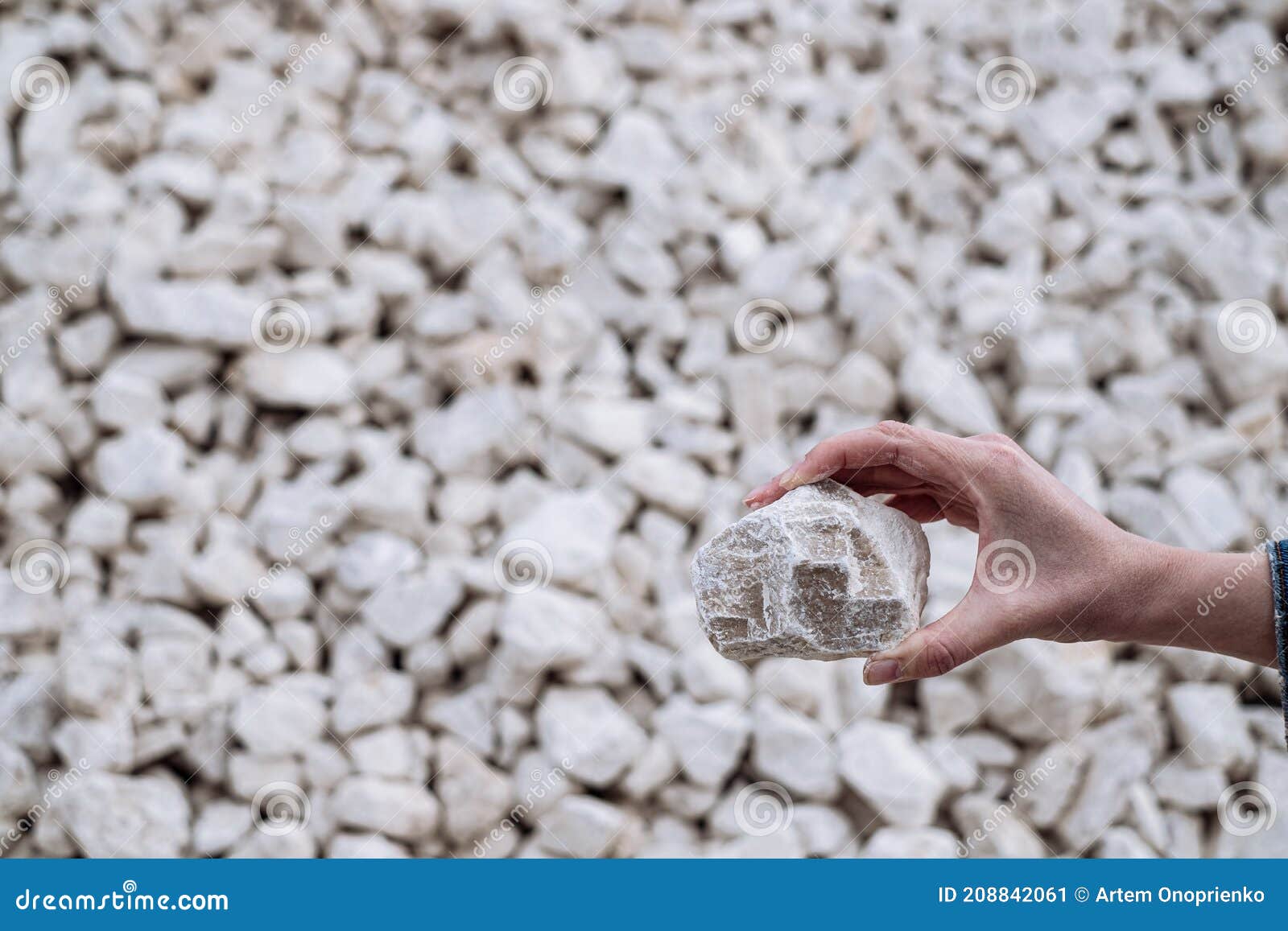 Hand Holds a White Chalkstone with a Lot of Stones on the Background ...