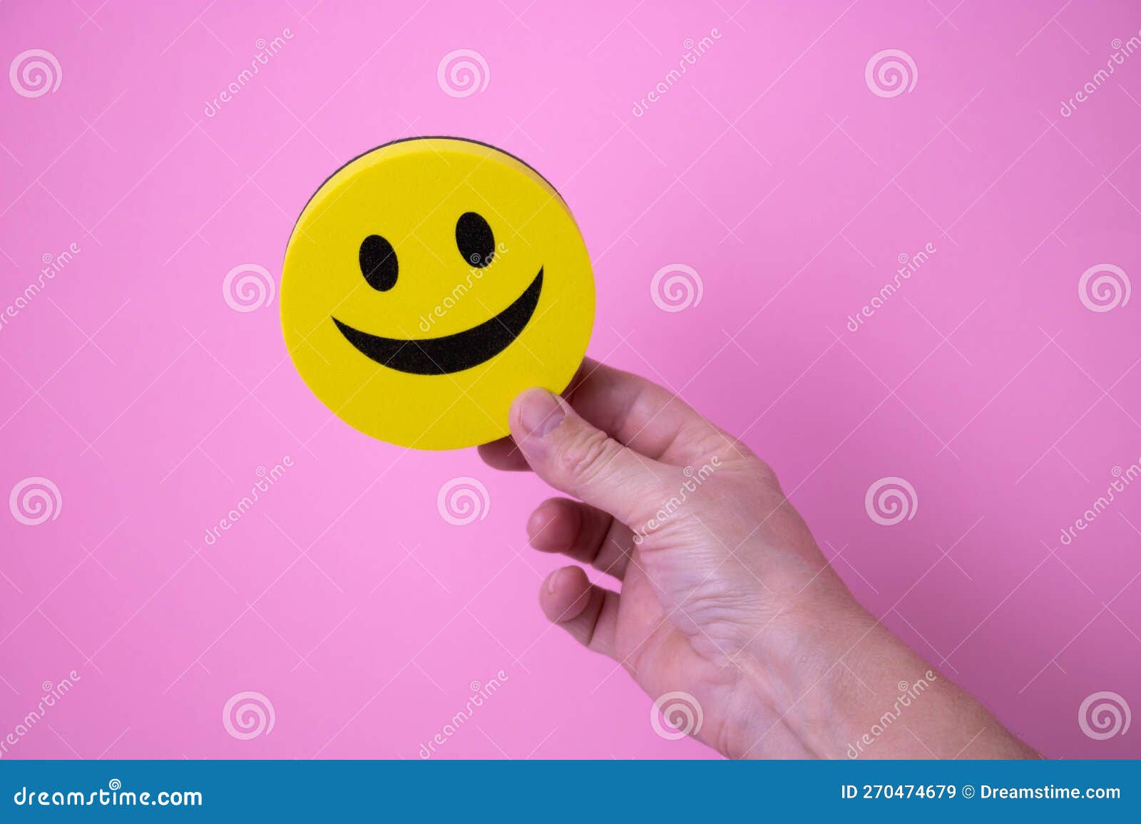 The Hand Holds a Yellow Smiling Smiley Face on a Pink Background Stock ...