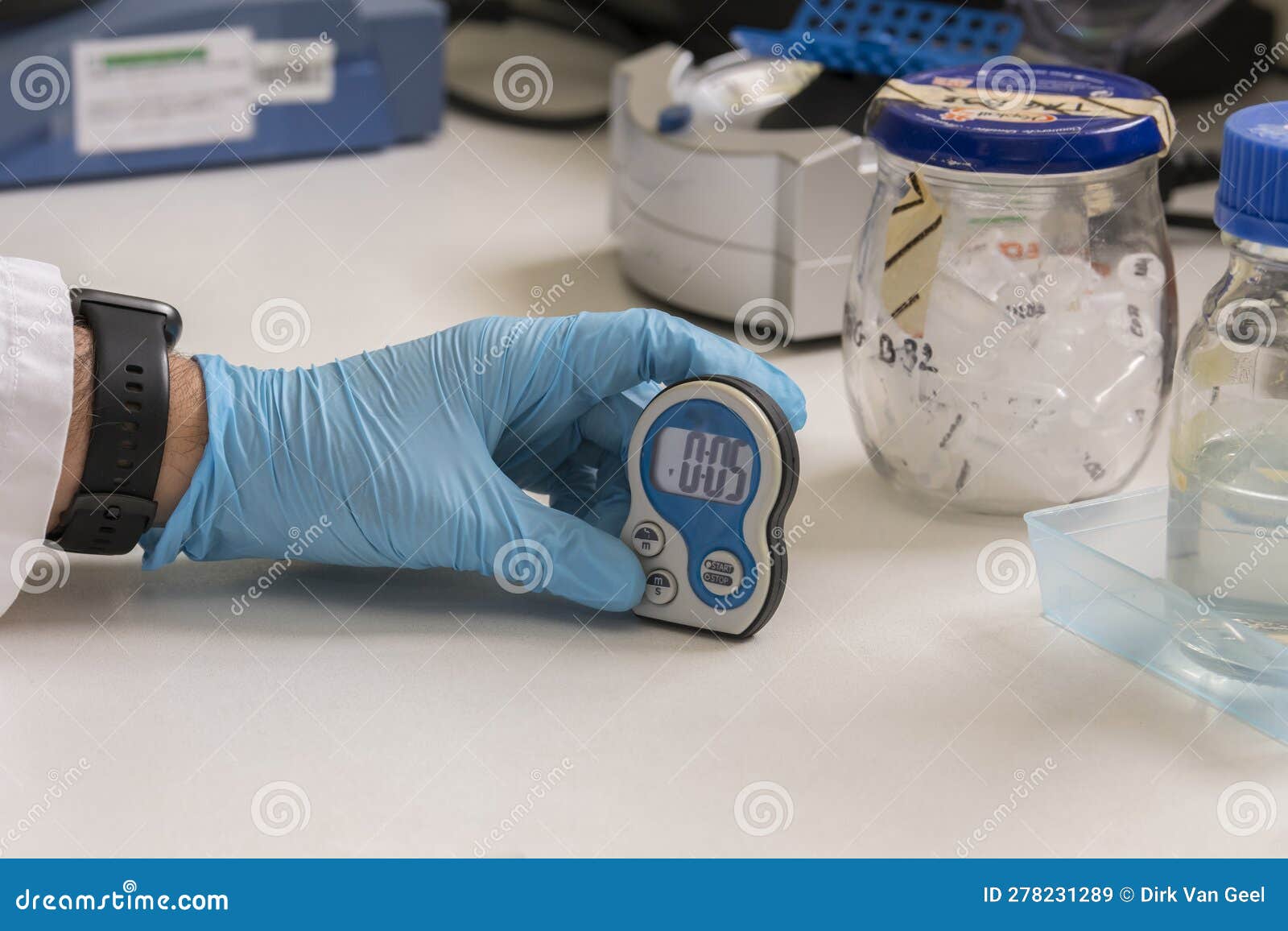 A Hand of a Lab Technician with Blue Nitril Gloves Holding an Timer in ...