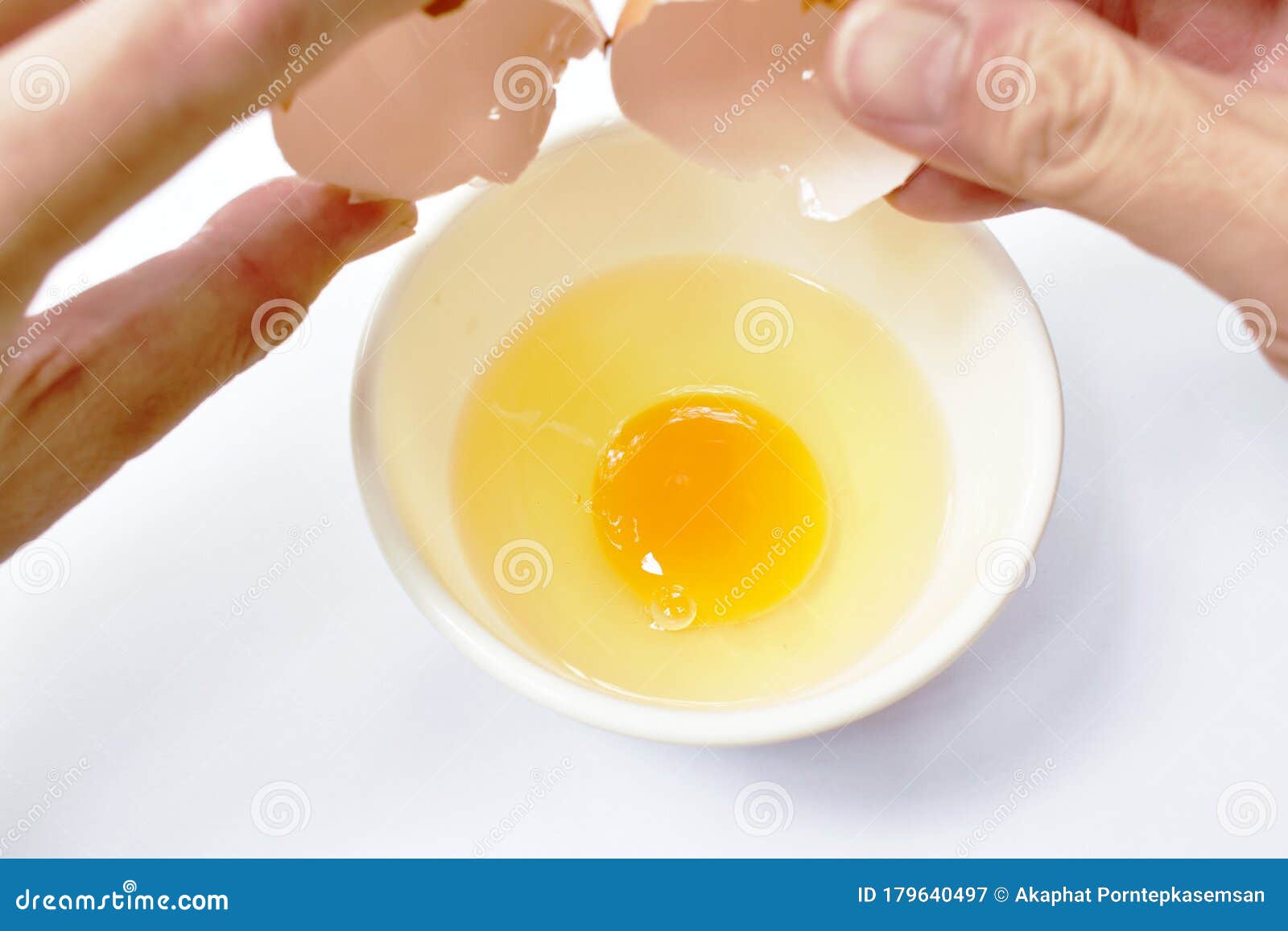 Hand Opened Shell and Raw Egg with Yolk Dropping in Cup on White ...
