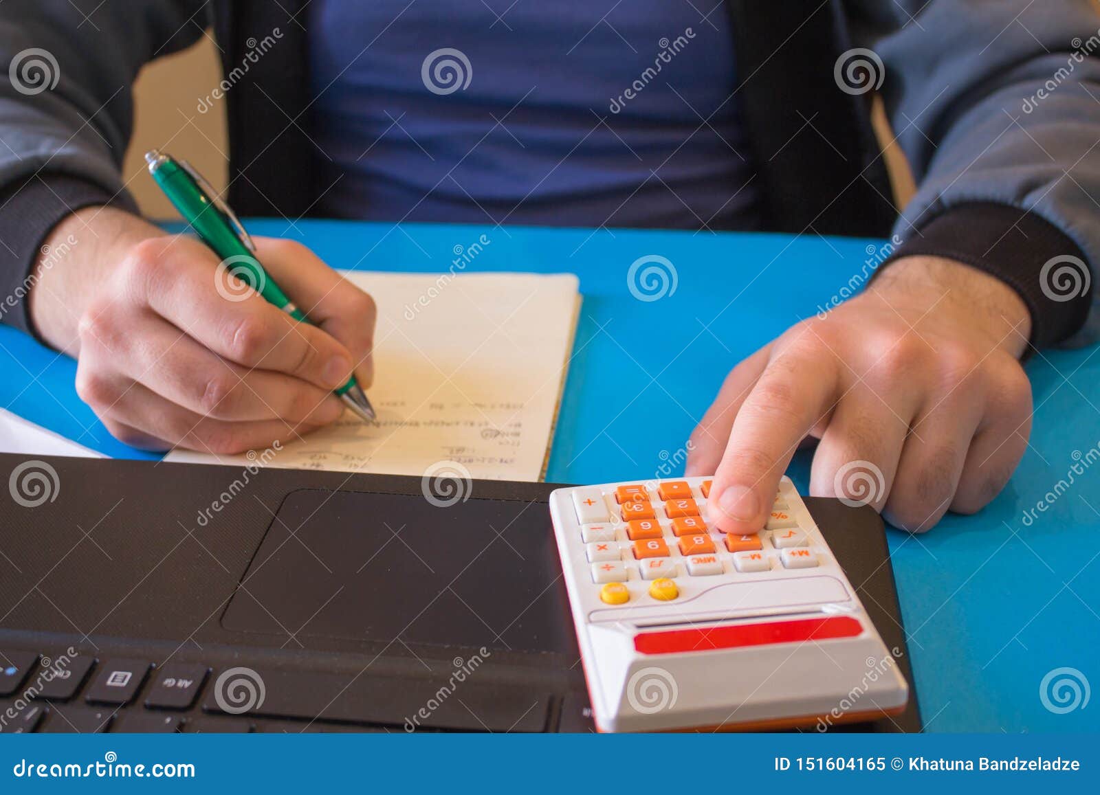 Hand with Pen, Calculator and Computer on Wooden Table. he is Using His ...
