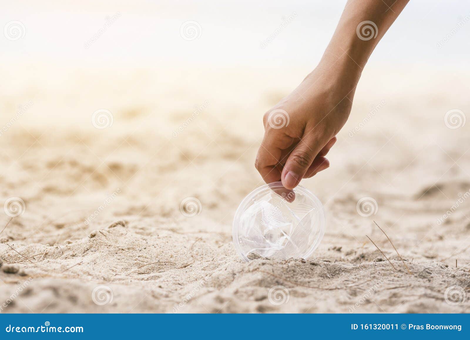 A Hand Picking Up a Plastic Glass Trash on the Beach Stock Image ...