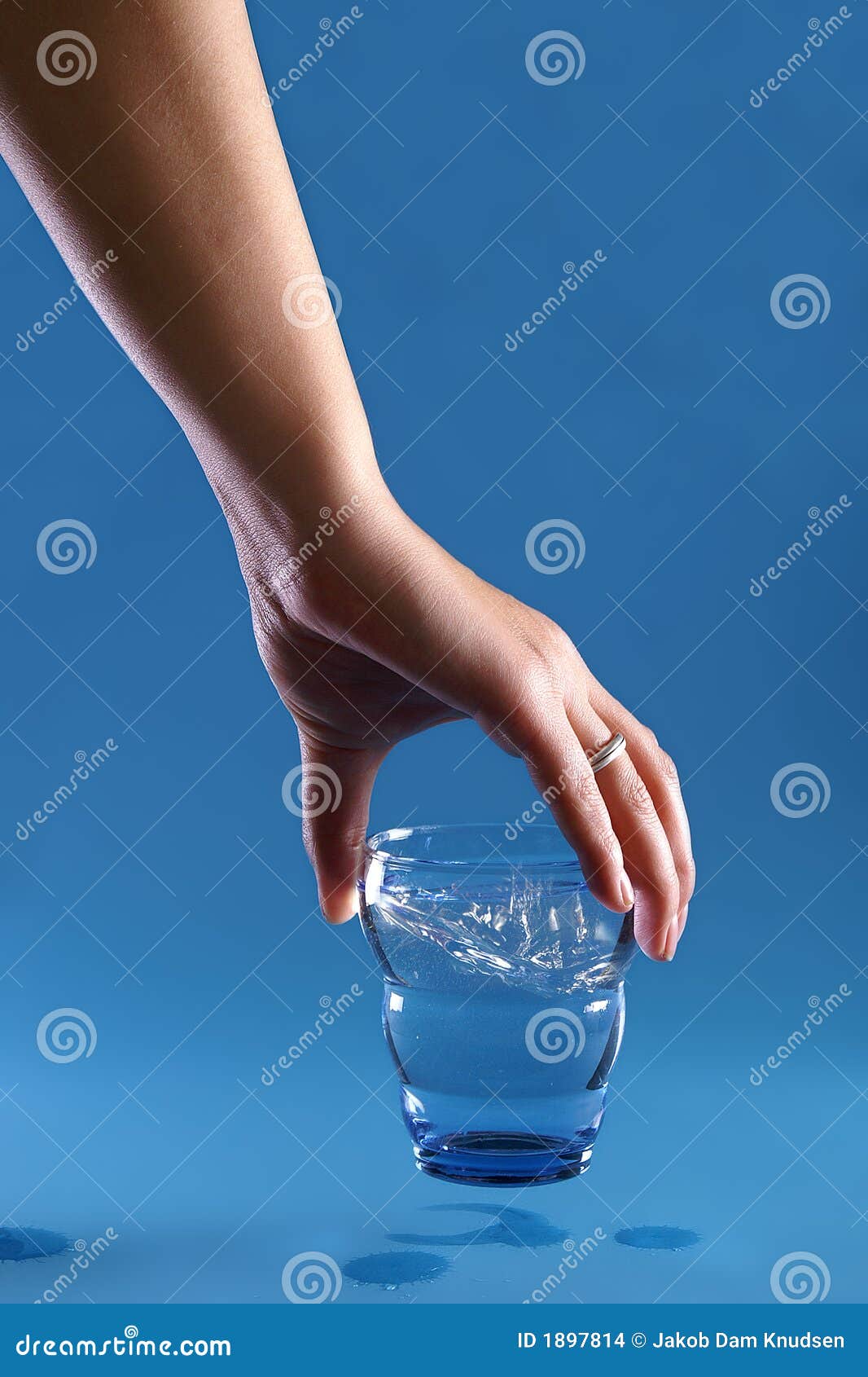 Hand Placing a Glass of Water on Blue Surface Stock Photo - Image of ...