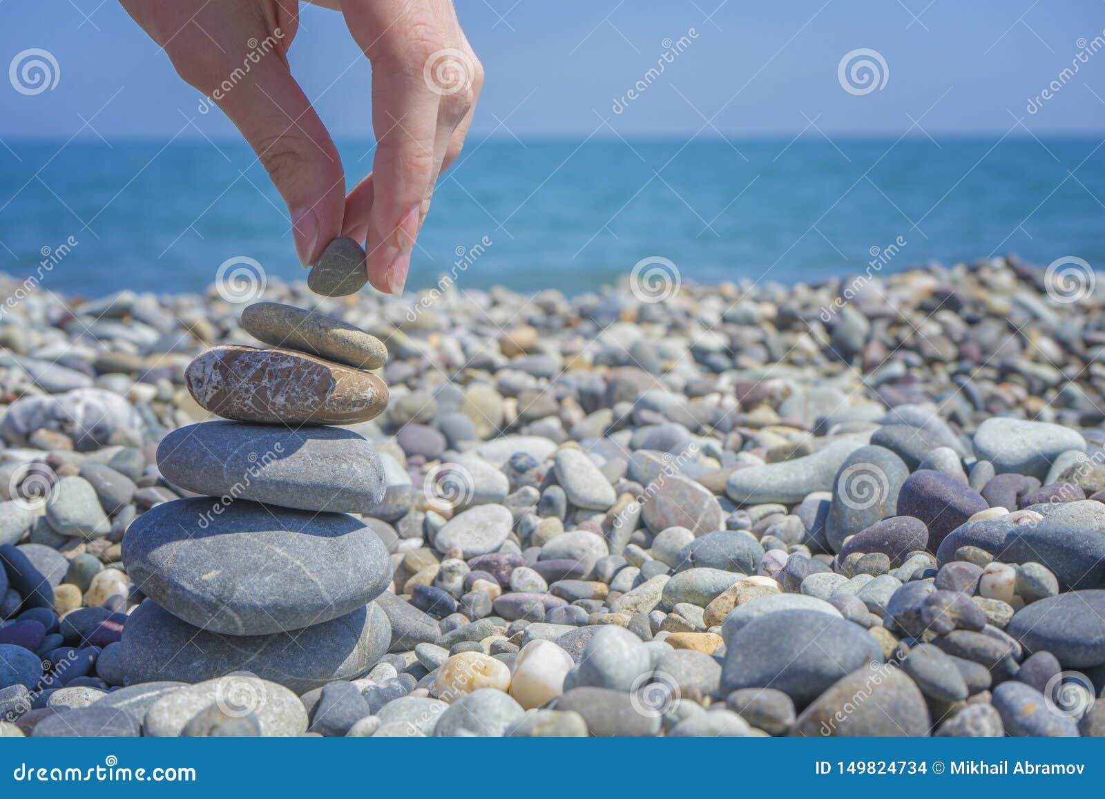 Hand Placing the Last Pebble of a Stacked Tower on the Sea Side Stock ...