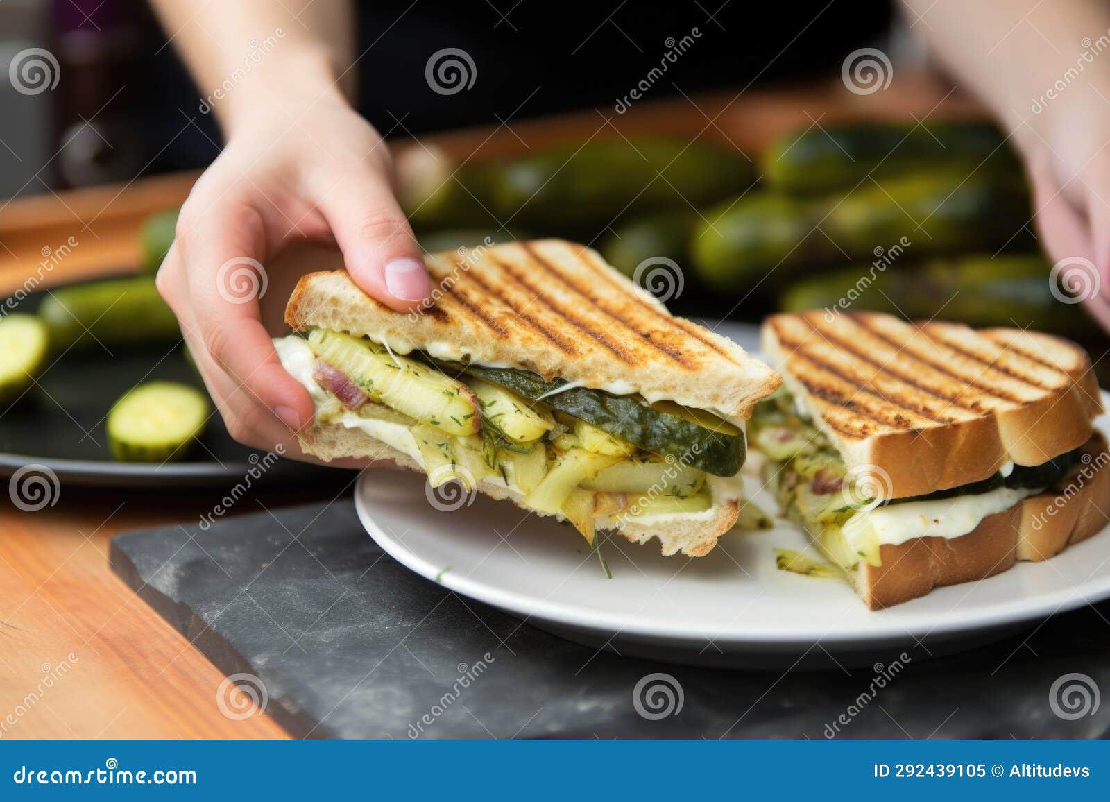Hand Placing Pickles on a Plate Next To a Grilled Sandwich Stock ...