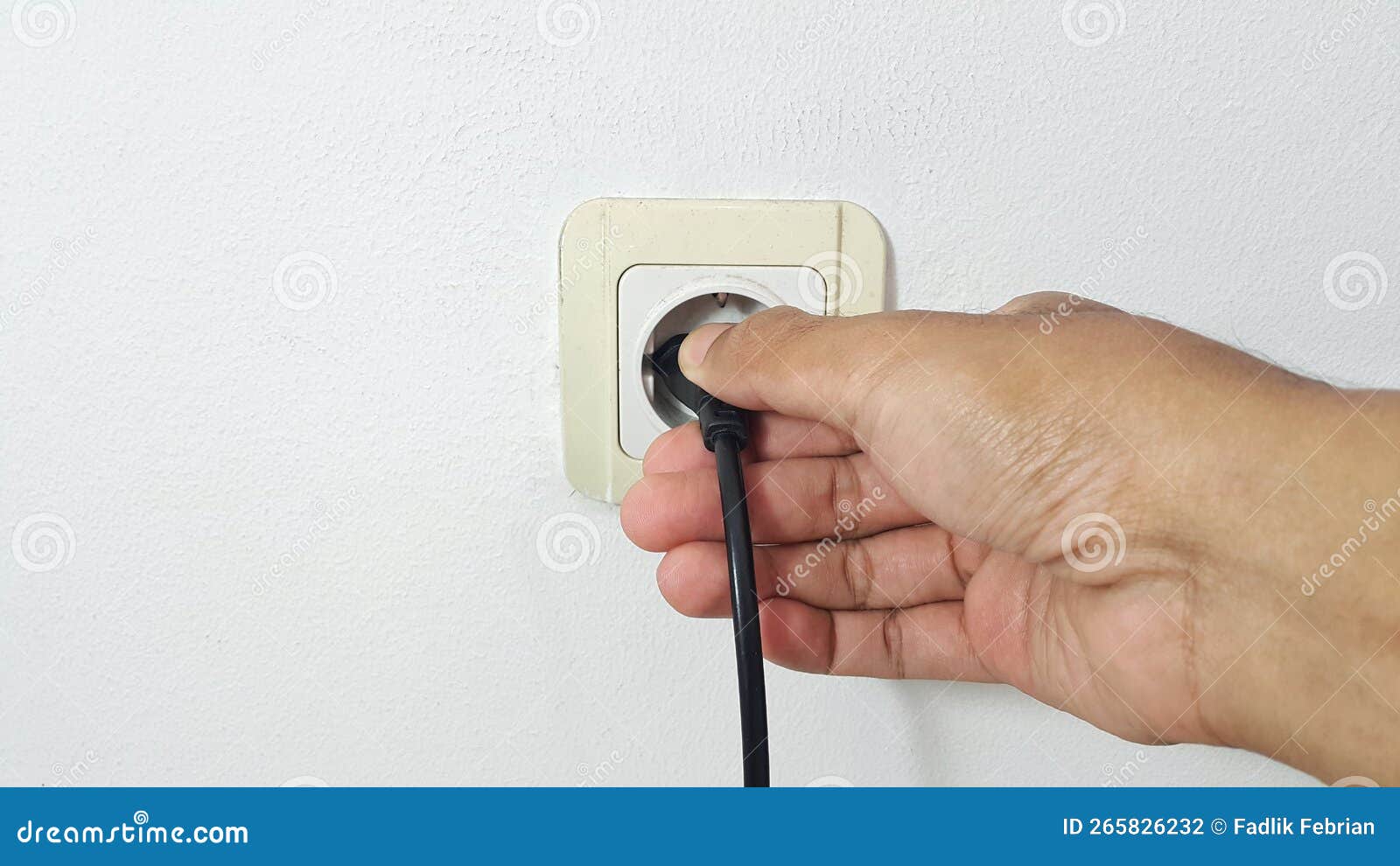 Hand Plugging in an Electric Cord into a White Plastic Socket on White ...