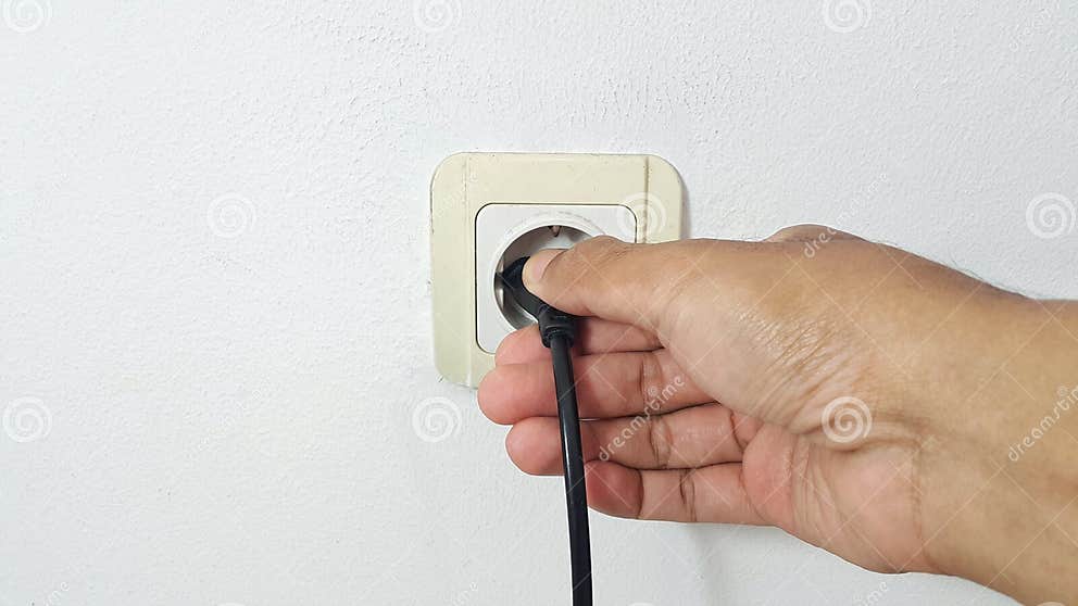 Hand Plugging in an Electric Cord into a White Plastic Socket on White ...