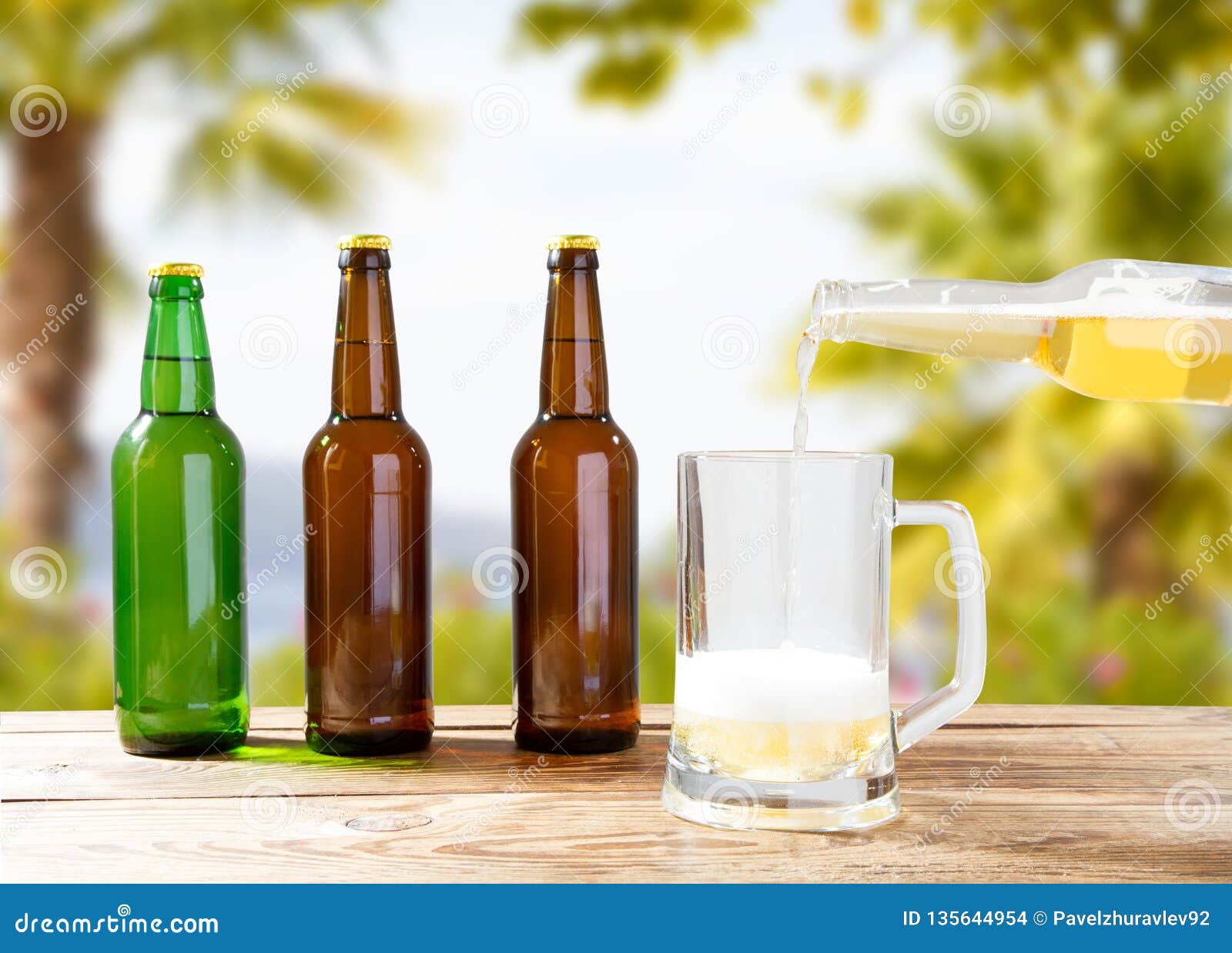 Hand Pouring Light Beer in a Cup, Bottles on Wooden Table Stock Photo ...