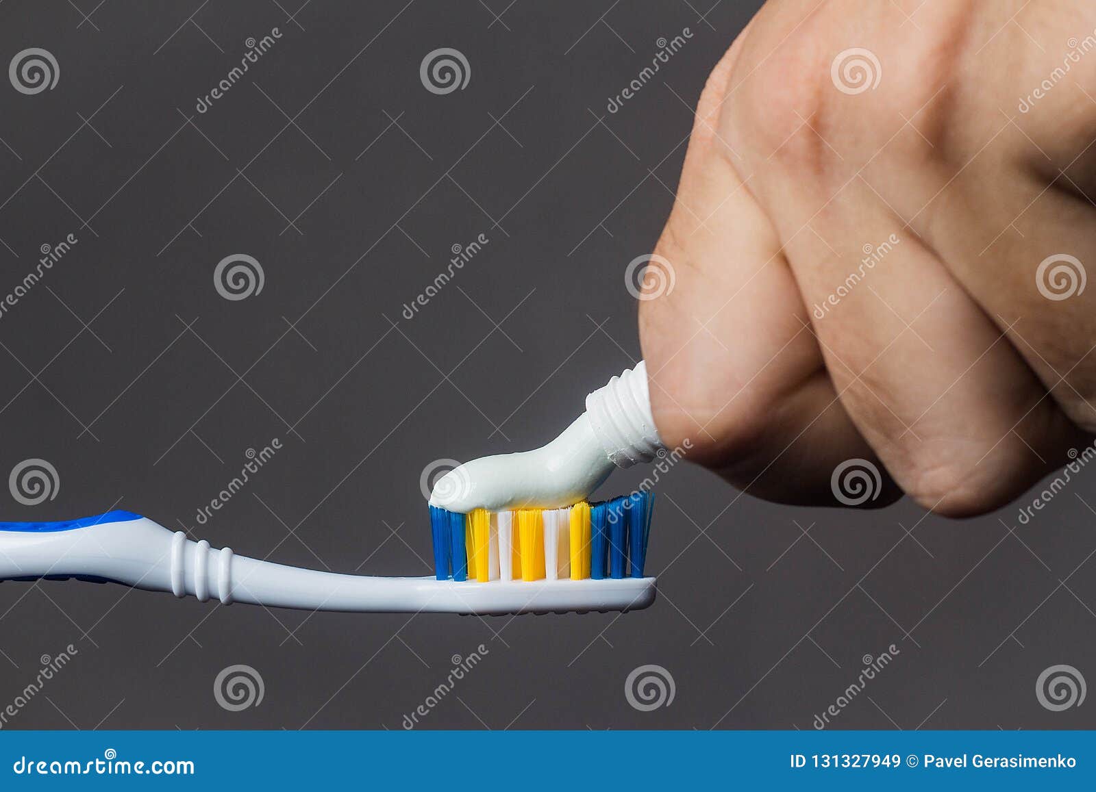 Hand Puts Toothpaste on the Toothbrush on a Gray Background Close-up ...