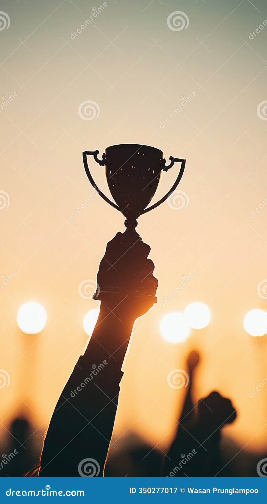 A Hand Raised Triumphantly Holding a Trophy Against a Glowing Sunset ...