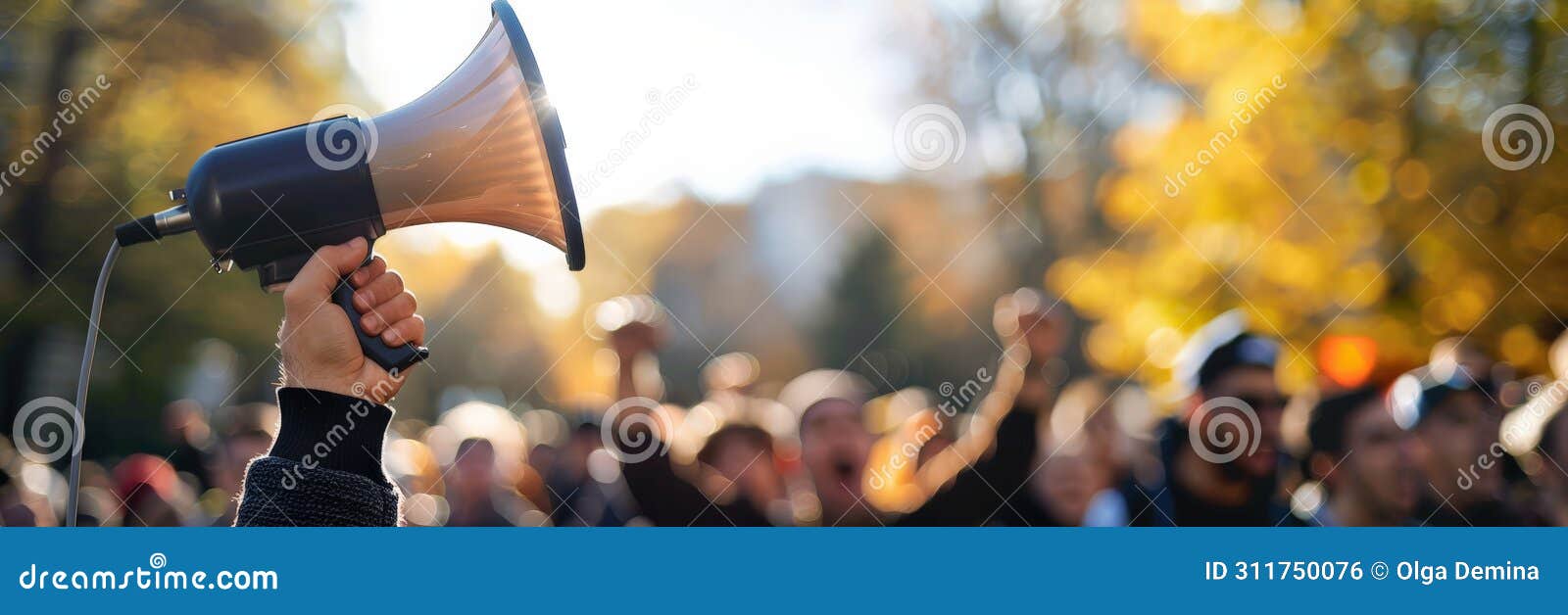 A Hand Raising a Megaphone Against a Backdrop of a Protesting Crowd and ...