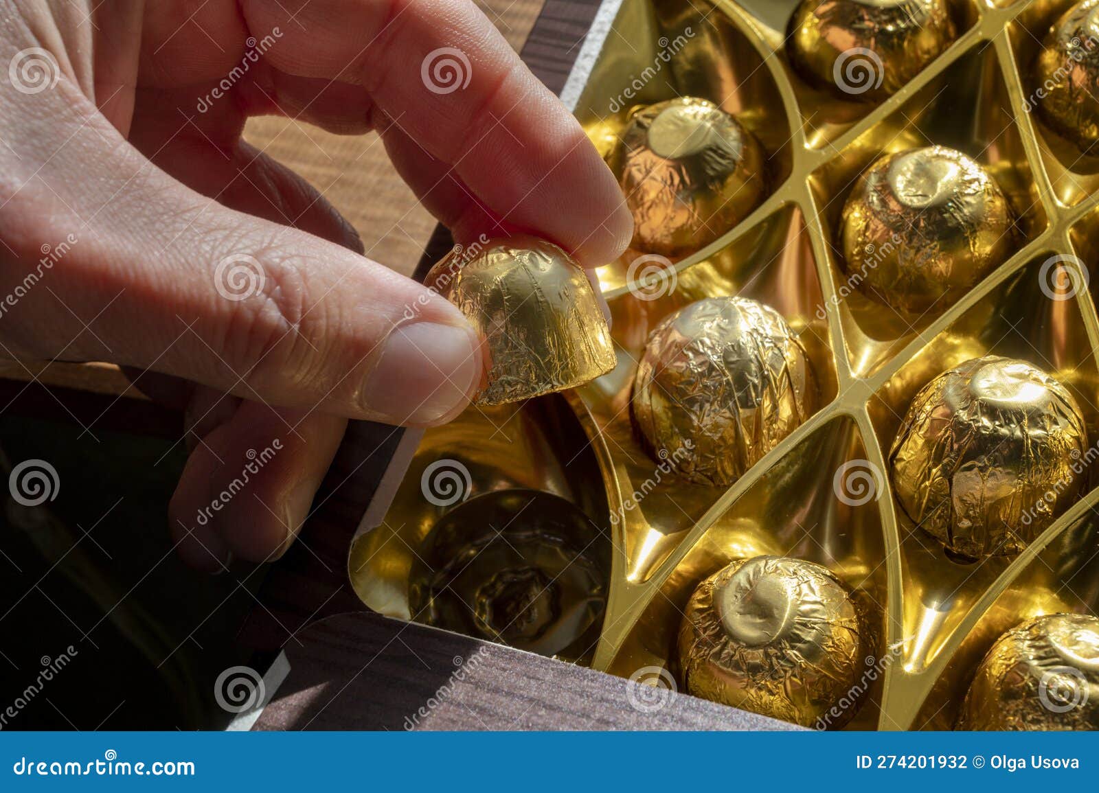 Hand Reaching for Chocolate in Golden Wrap in Box, Closeup View Stock ...
