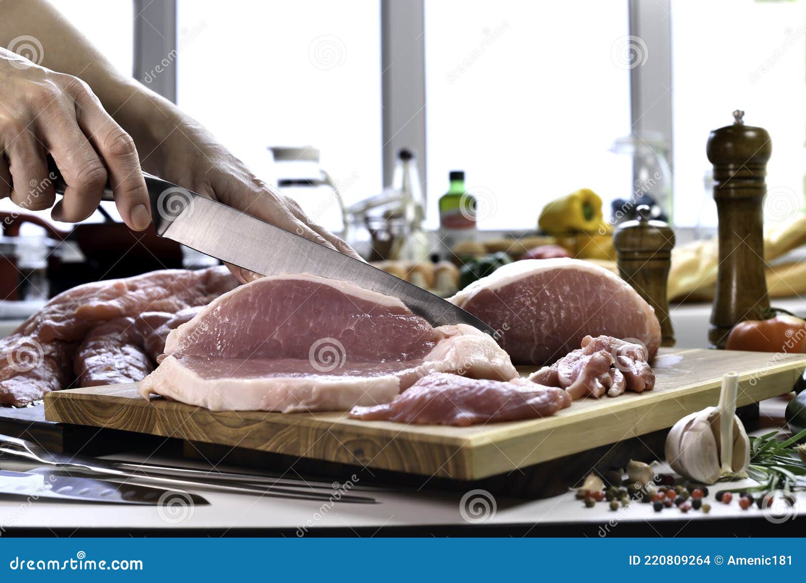 Hand Slicing Fresh Raw Pork Meat on a Cutting Board in the Kitchen ...