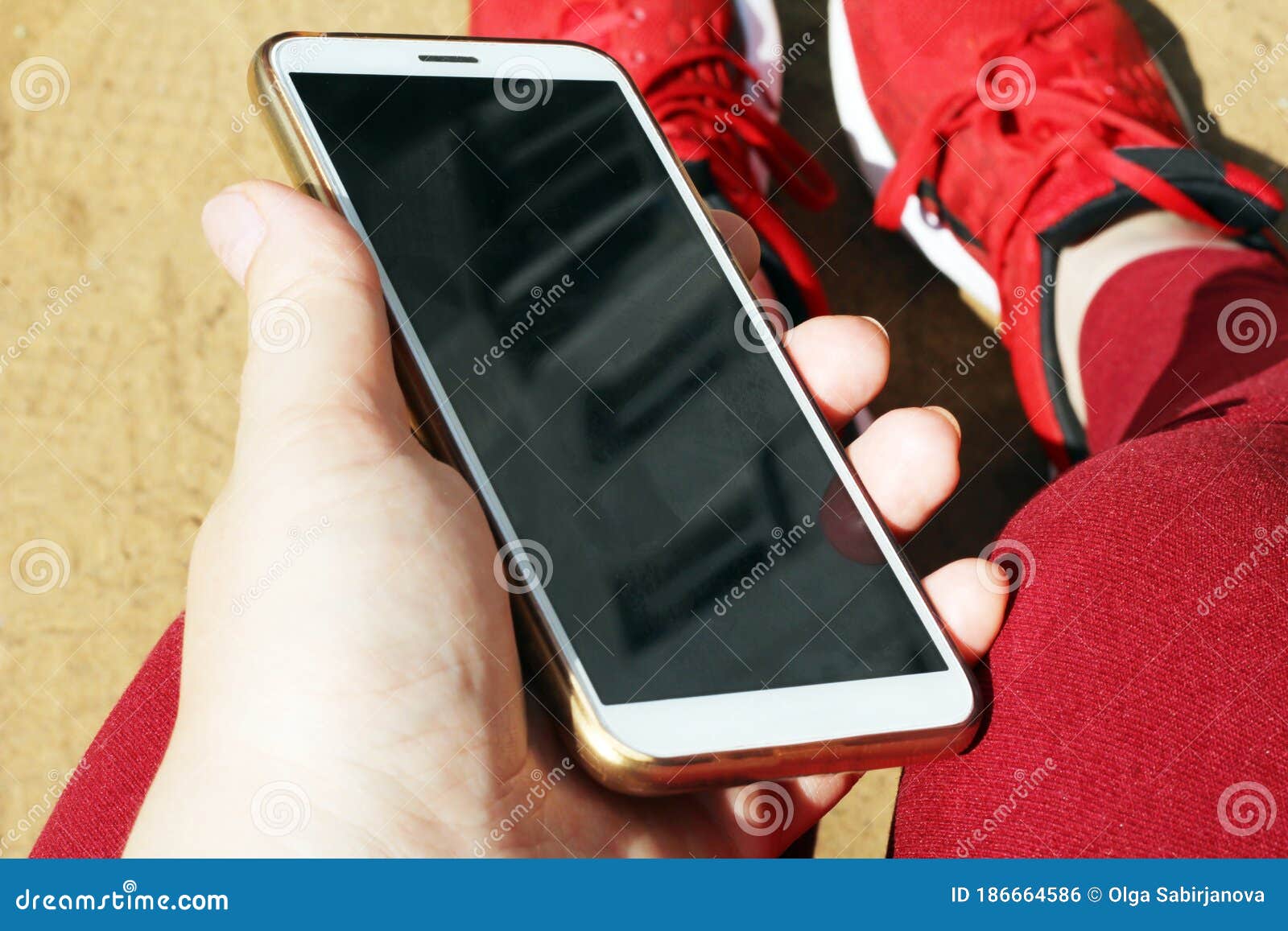 Hand with a Smartphone on the Background of Feet and Red Sneakers Stock ...