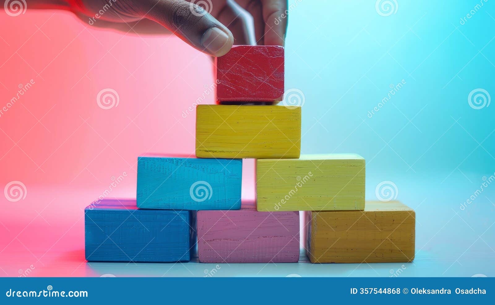 A Hand Stacking Colorful Wooden Blocks in a Pyramid Shape. Stock Photo ...