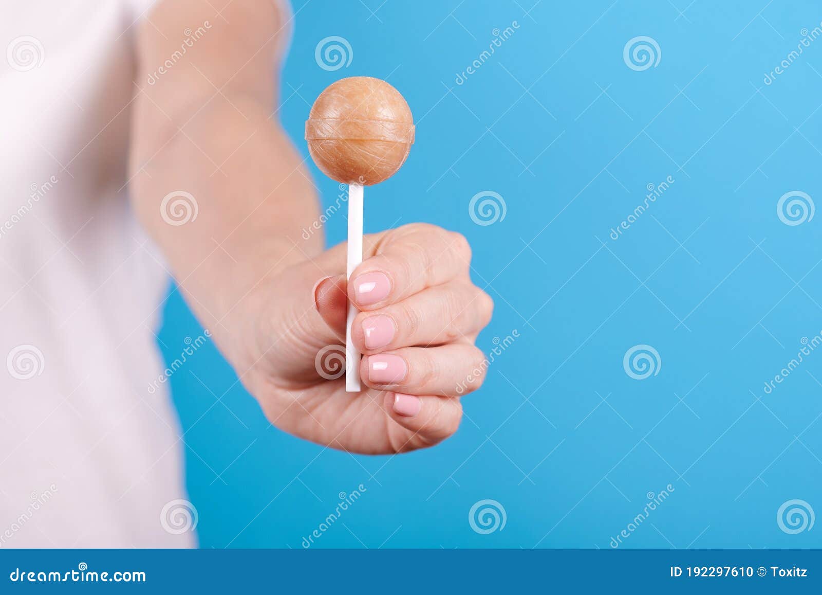 Hand with Sweet Caramel Lollipop. Isolated on Blue Background Stock ...