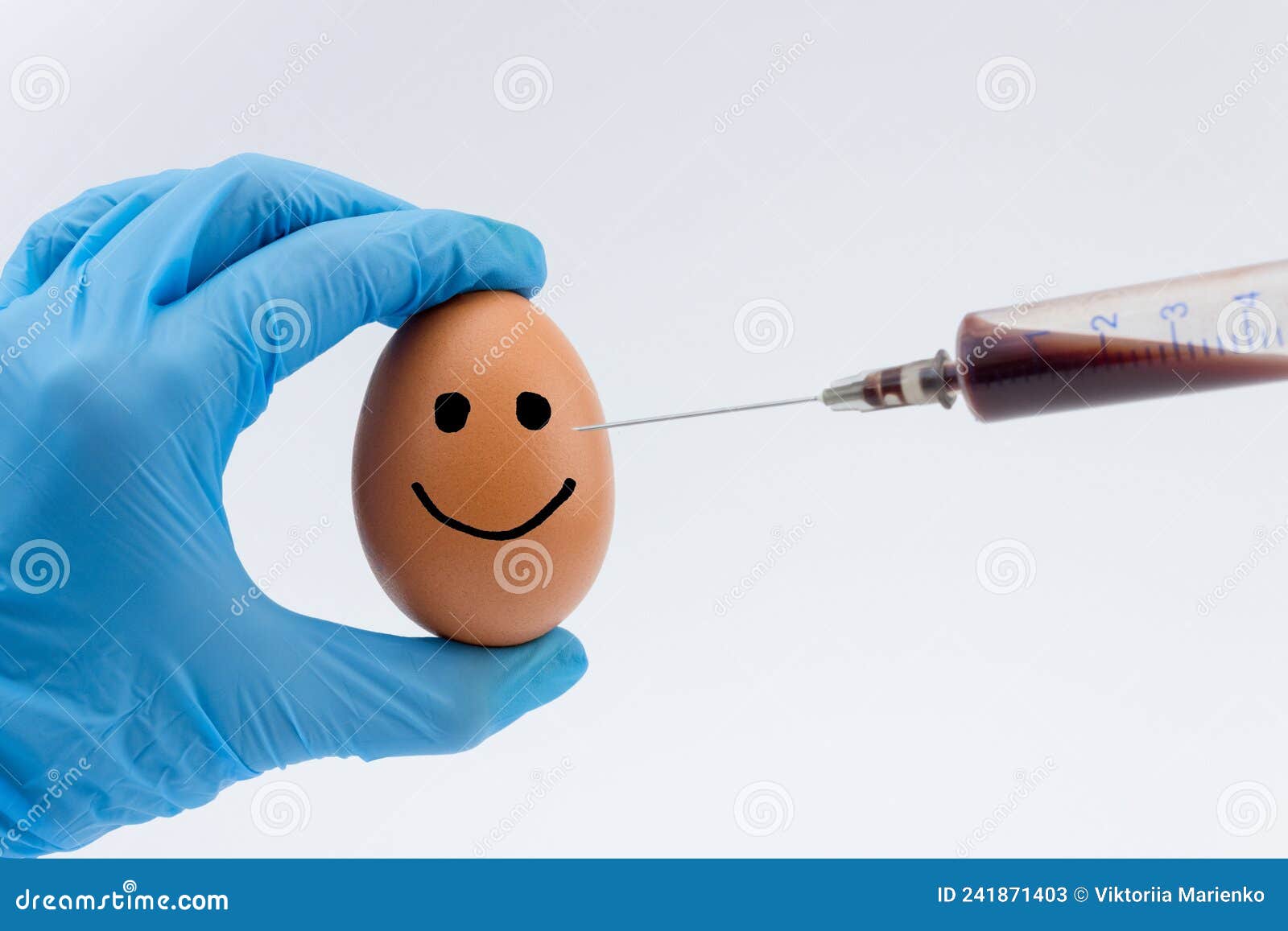 A Hand with a Syringe Makes an Injection into the Egg Close-up. the ...
