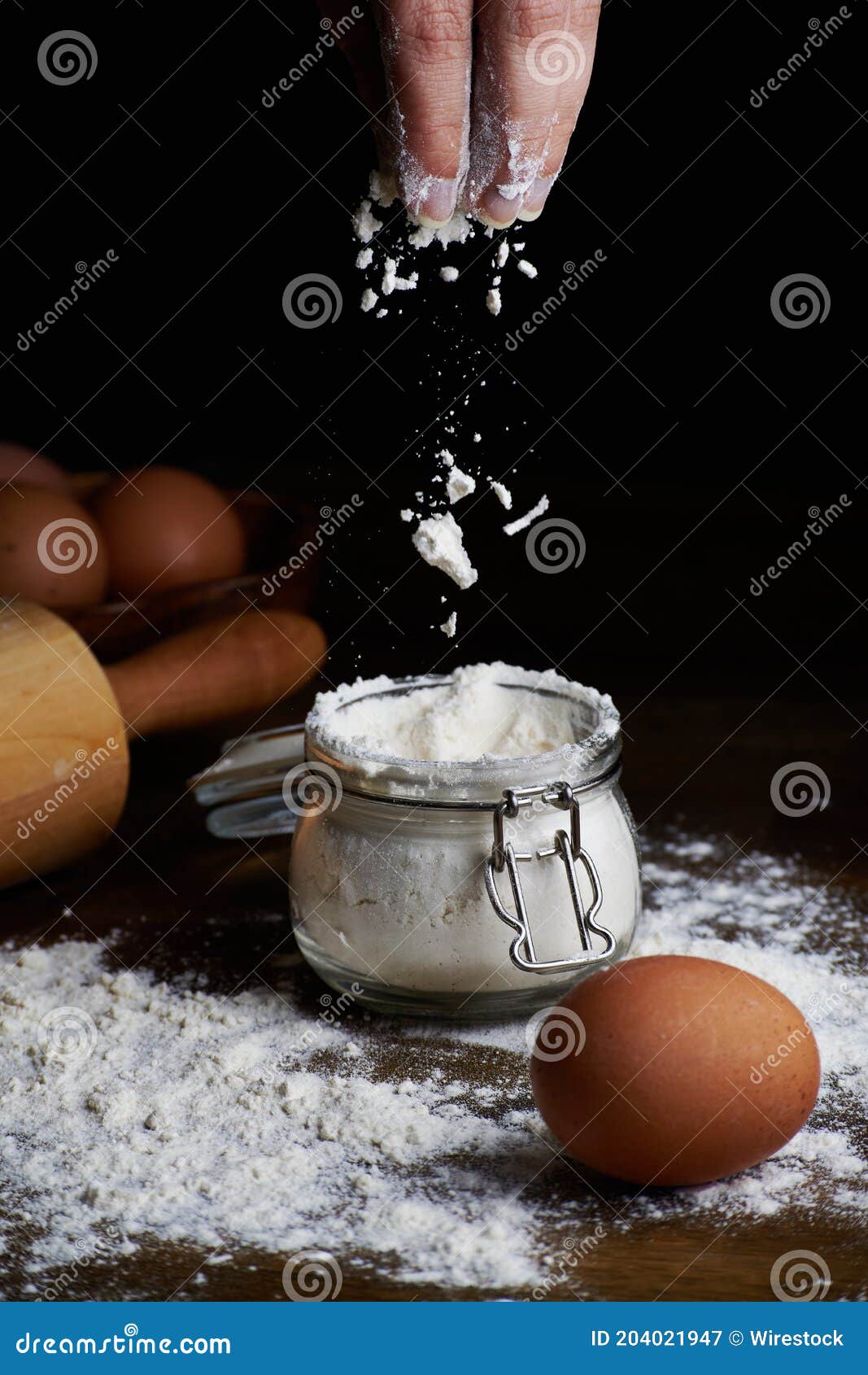 Hand Taking Flour from a Bowl with Eggs and a Rolling Pin on the Table ...