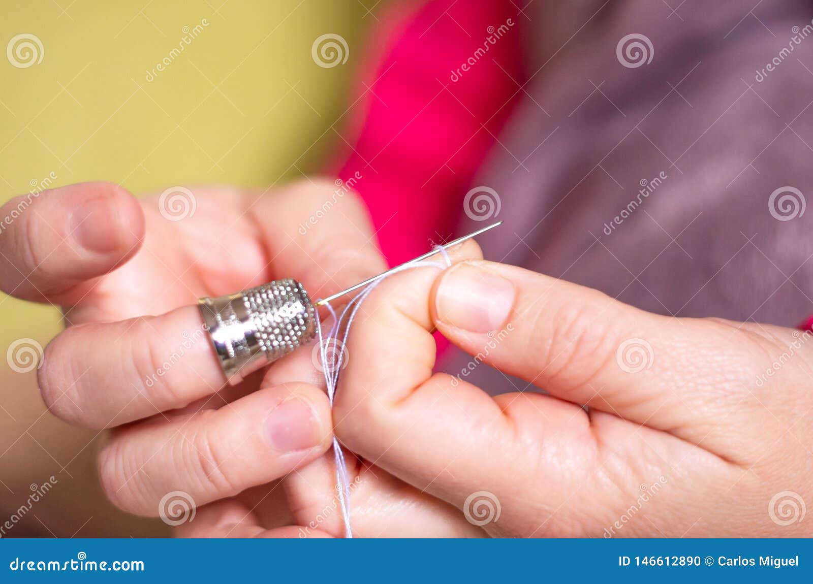 A Hand with Thimble Knotting and Cutting a Thread on a Needle in a ...