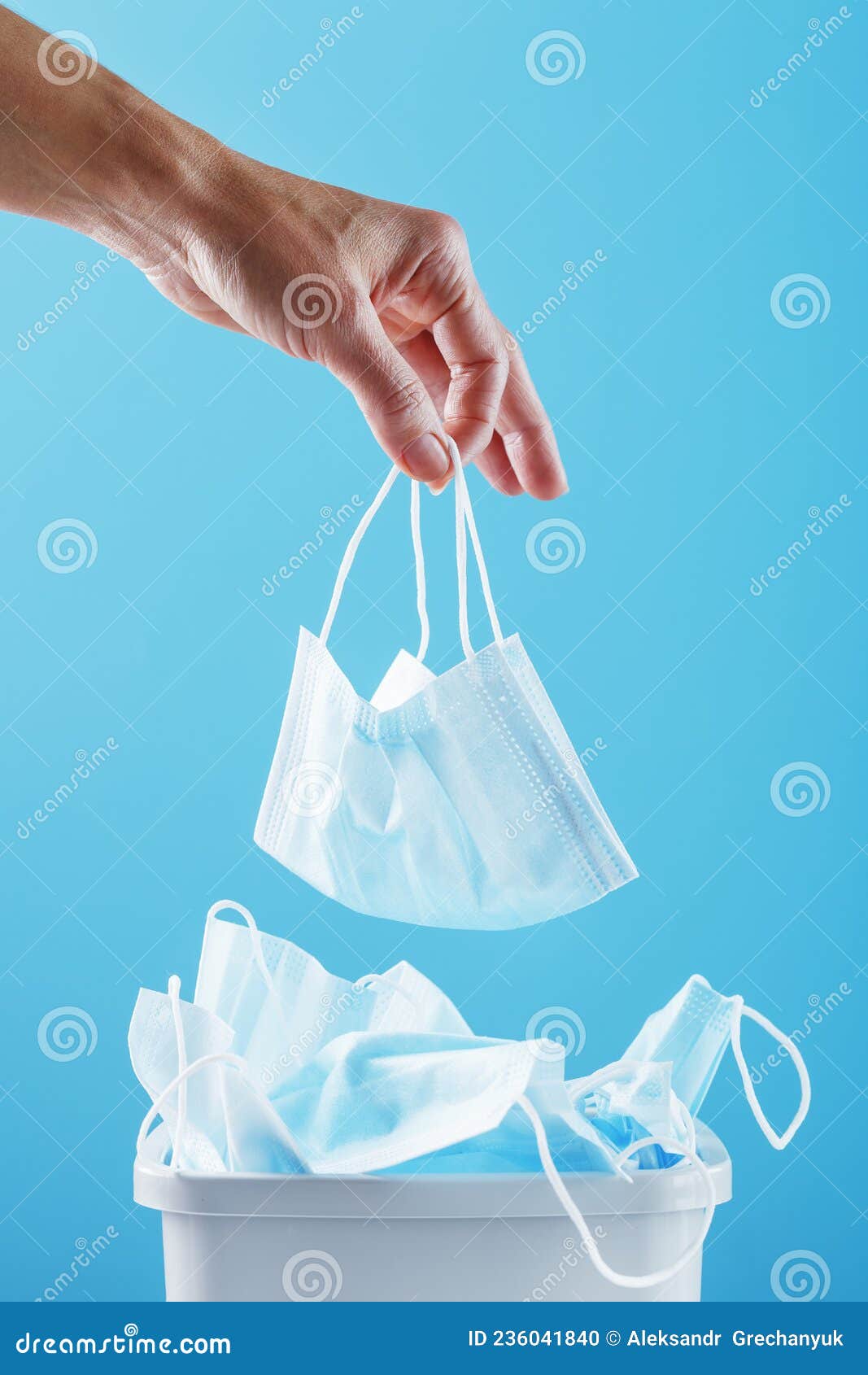 Hand Throws a Used Face Shield into the Trash Can on a Light Blue ...