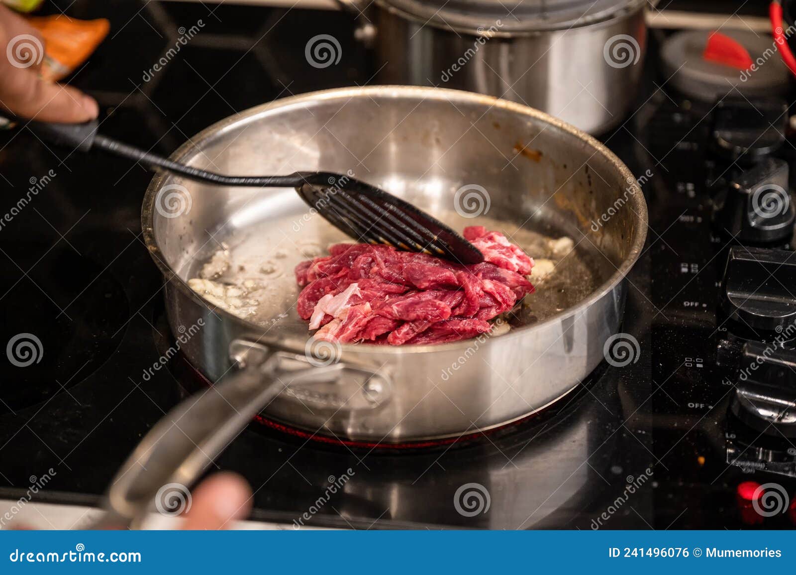 Hand Using Kitchen Flipper Frying Sliced Beef in Iron Pan on Stove ...