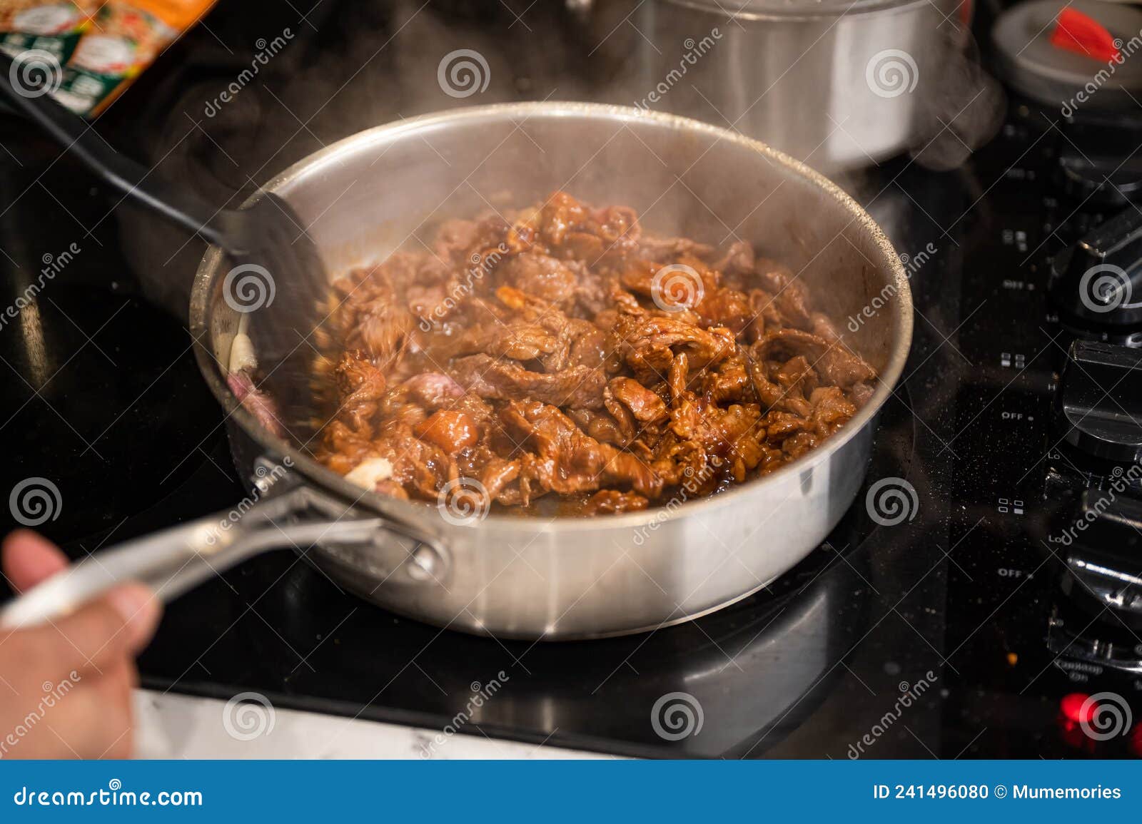 Hand Using Kitchen Flipper Frying Sliced Beef in Iron Pan on Stove ...