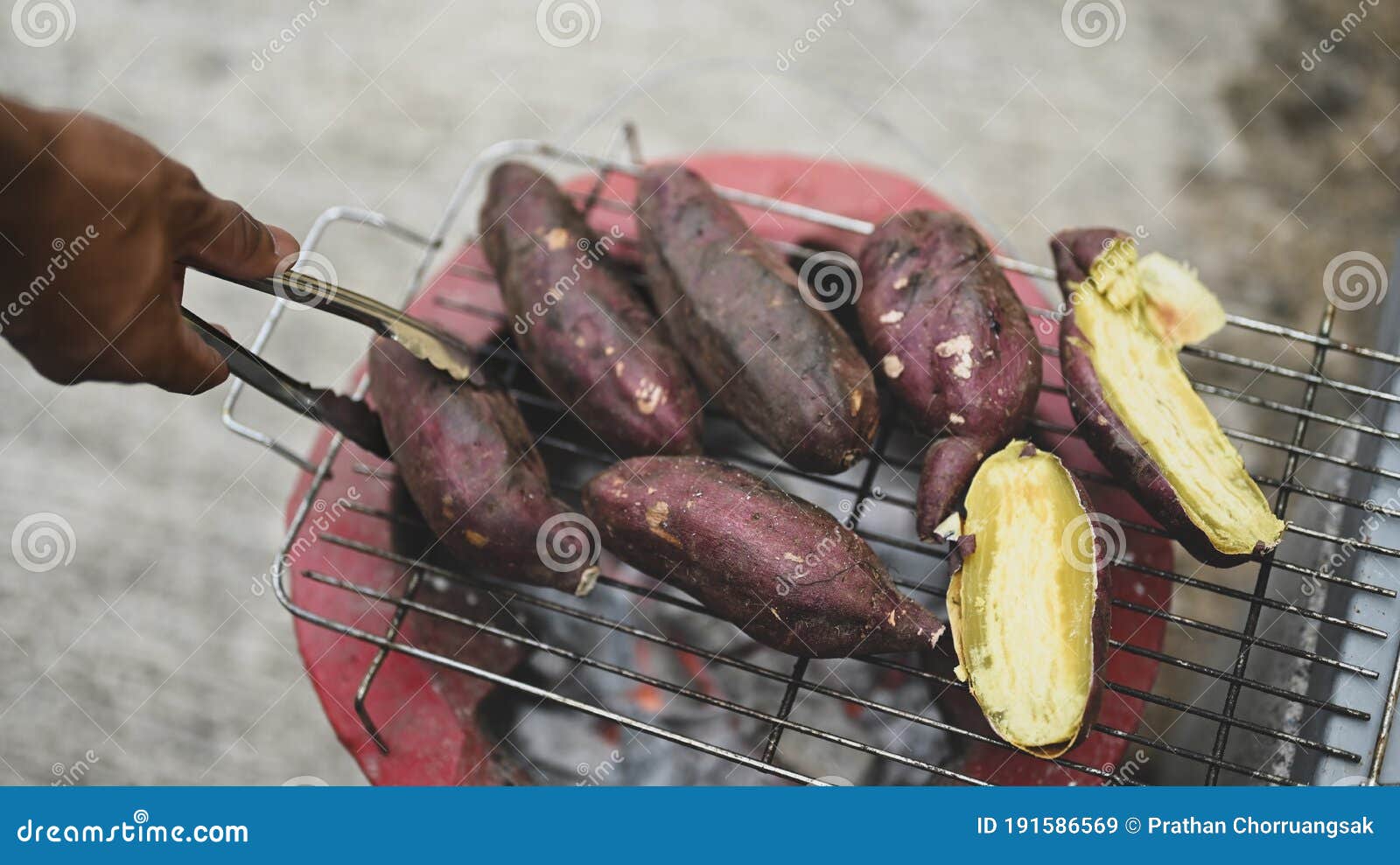 A Hand is Using Tongs for Grilling Rustic Potatoes on the Charcoal ...