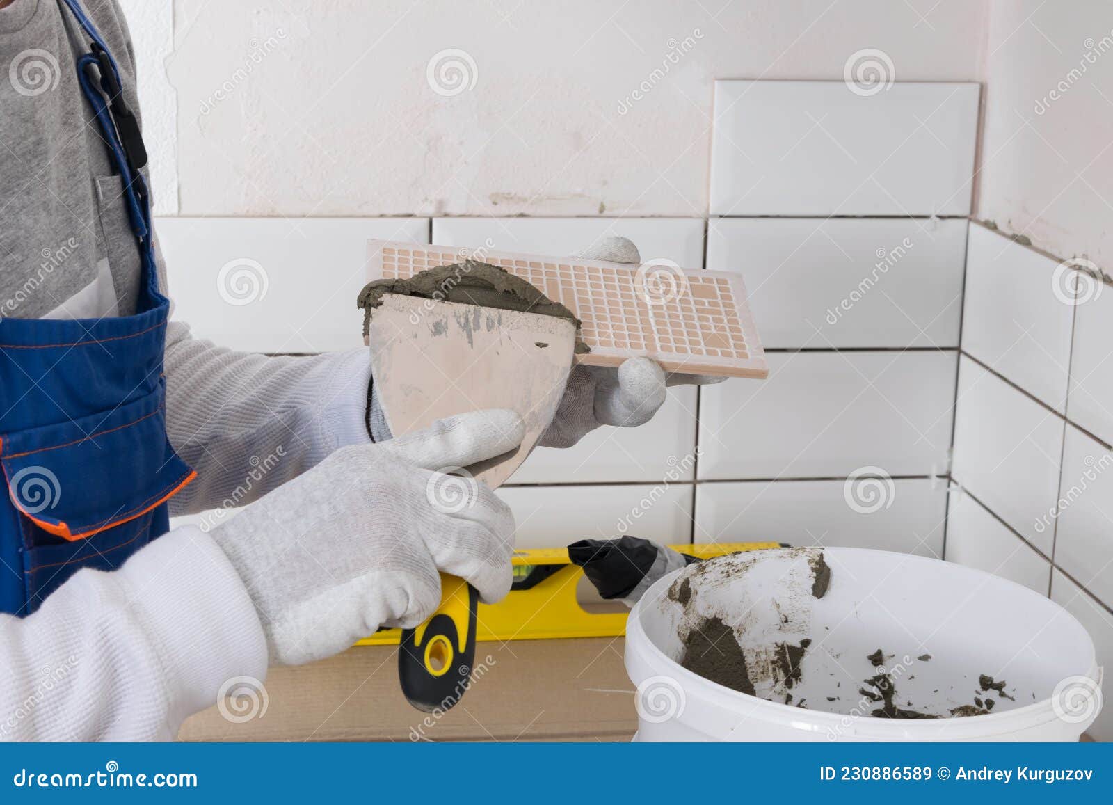 In the Hand of a Worker in a Protective Glove, a White Tile with a ...