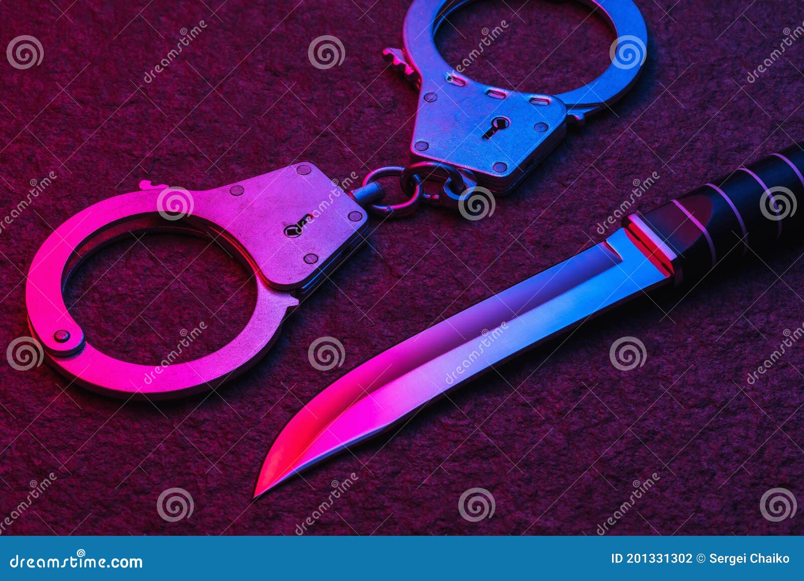 Handcuffs and a Knife on a Stone Surface Illuminated with Multi-colored ...