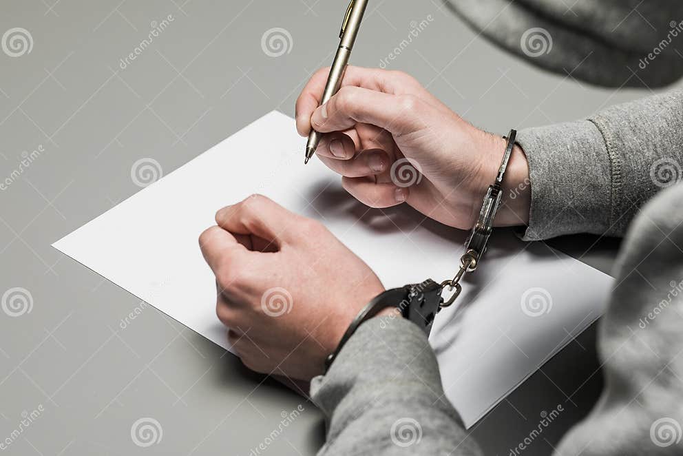 Hands of the Criminal in Handcuffs Write a Handle on Paper. Sincere ...