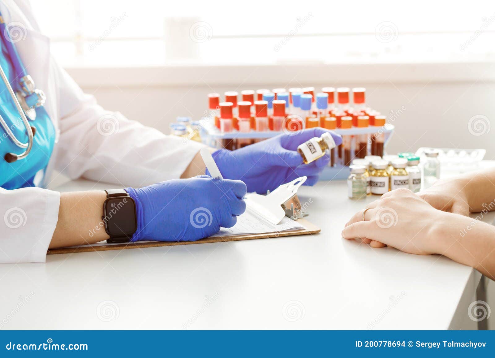 Hands of a Doctor Holding Blood Sample and Making Notes Stock Photo ...