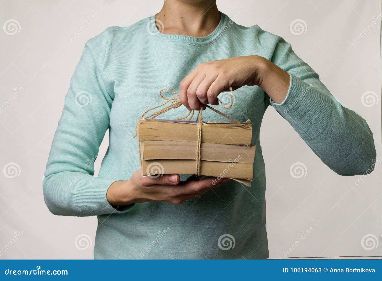 Hands Holding a Bunch of Books Connected by String, Rope on a Li Stock ...