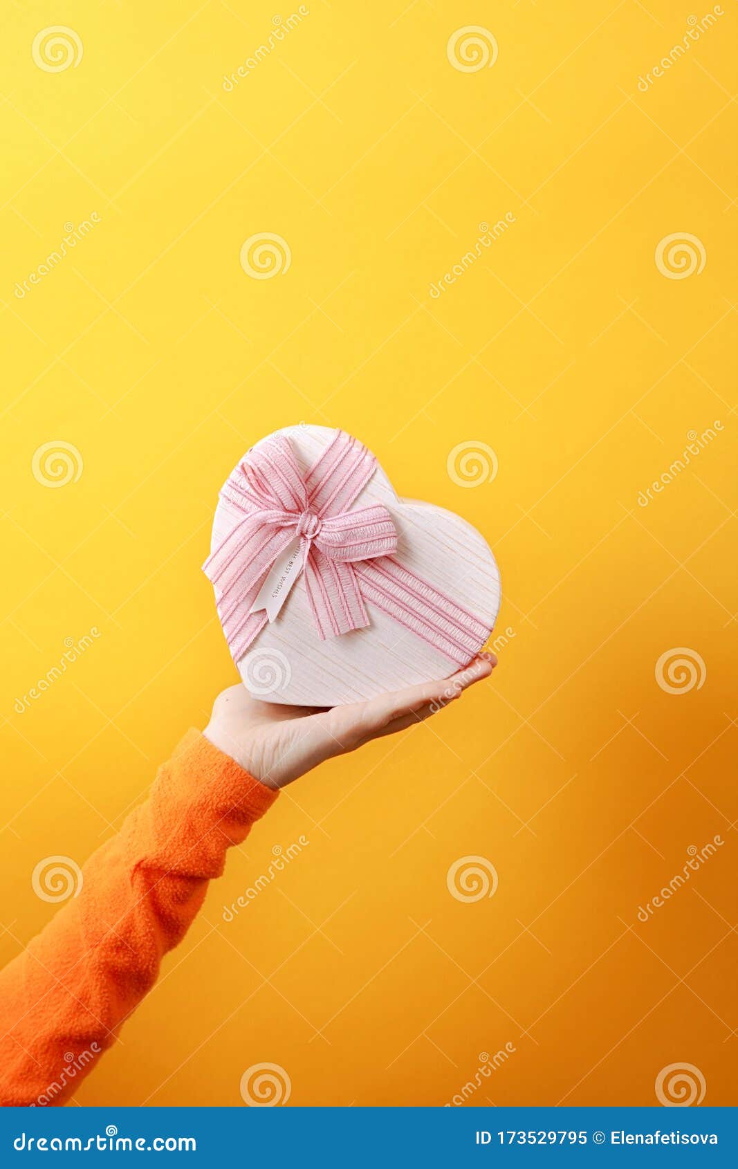 Hands Holding a Gift in the Form of a Heart on a Yellow Background ...