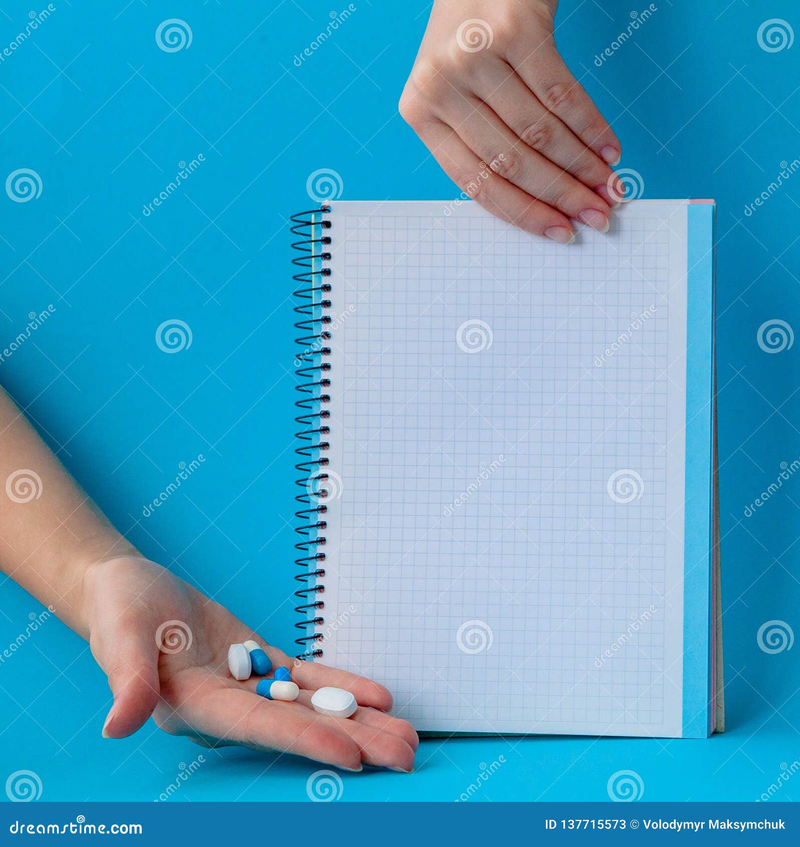 Hands Holding Pills and Notebook on a Blue Background Stock Image ...