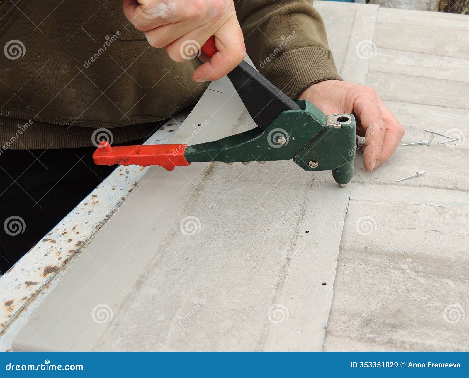 Hands Holding a Rivet Gun and Inserting Staples into an Iron Sheet ...