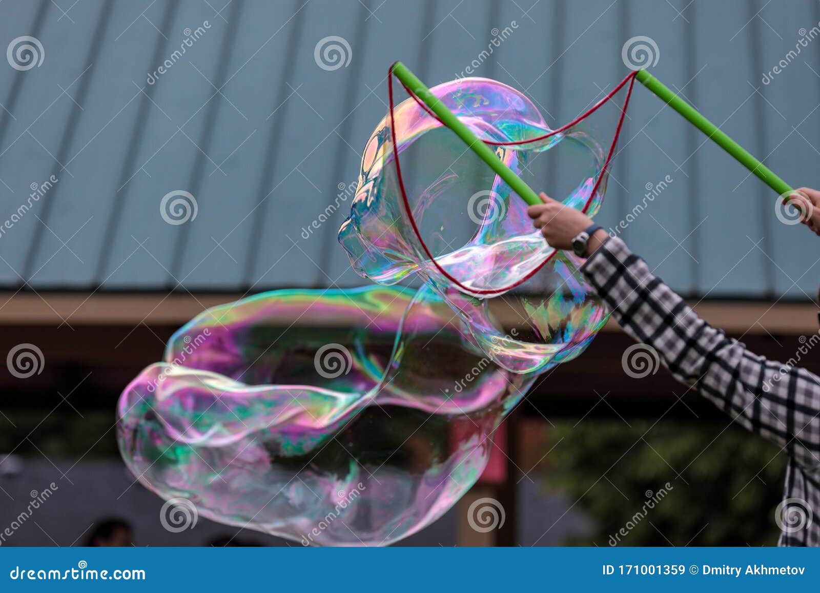 A Hands Holding Two Bubble Wands Making Giant Colorful Bubbles Stock ...