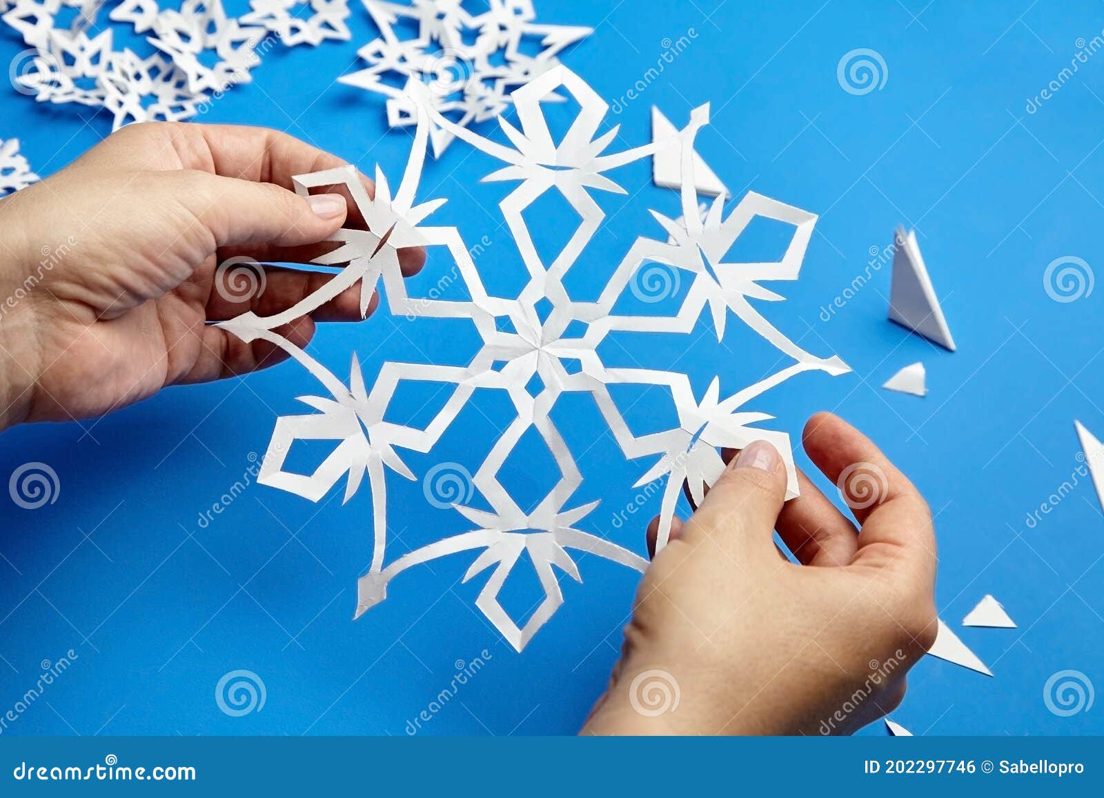 Hands Holding Cutted Paper Snowflake on Blue Surface Stock Photo ...