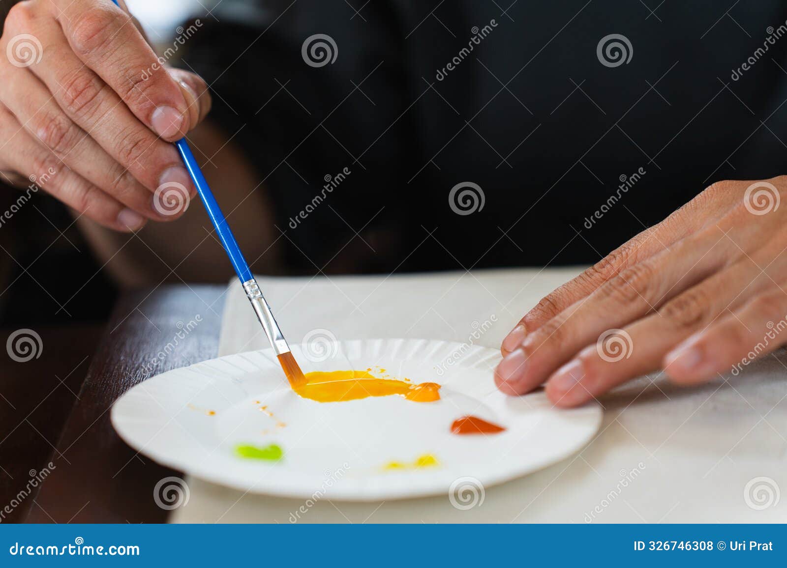 Hands of a Man Picking Up Paint with a Brush from the Color Palette ...