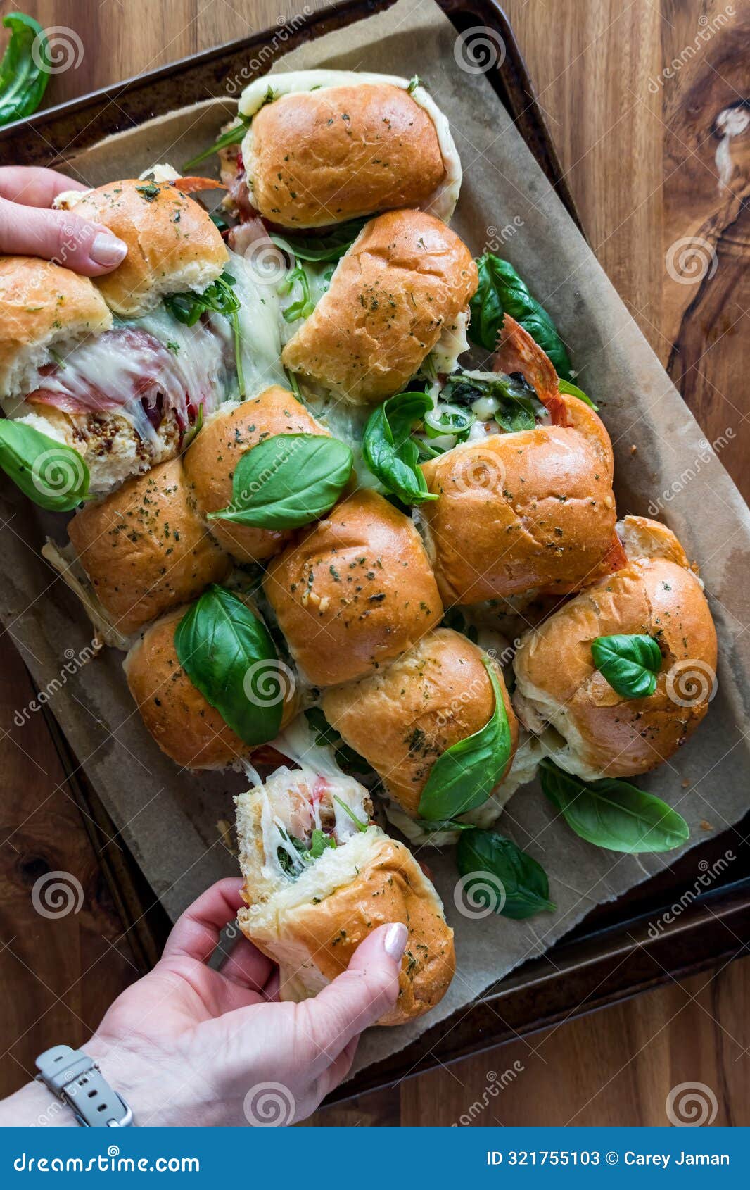 Hands Pulling at Buns from a Tray of Cheesy Italian Sub Sliders. Stock ...