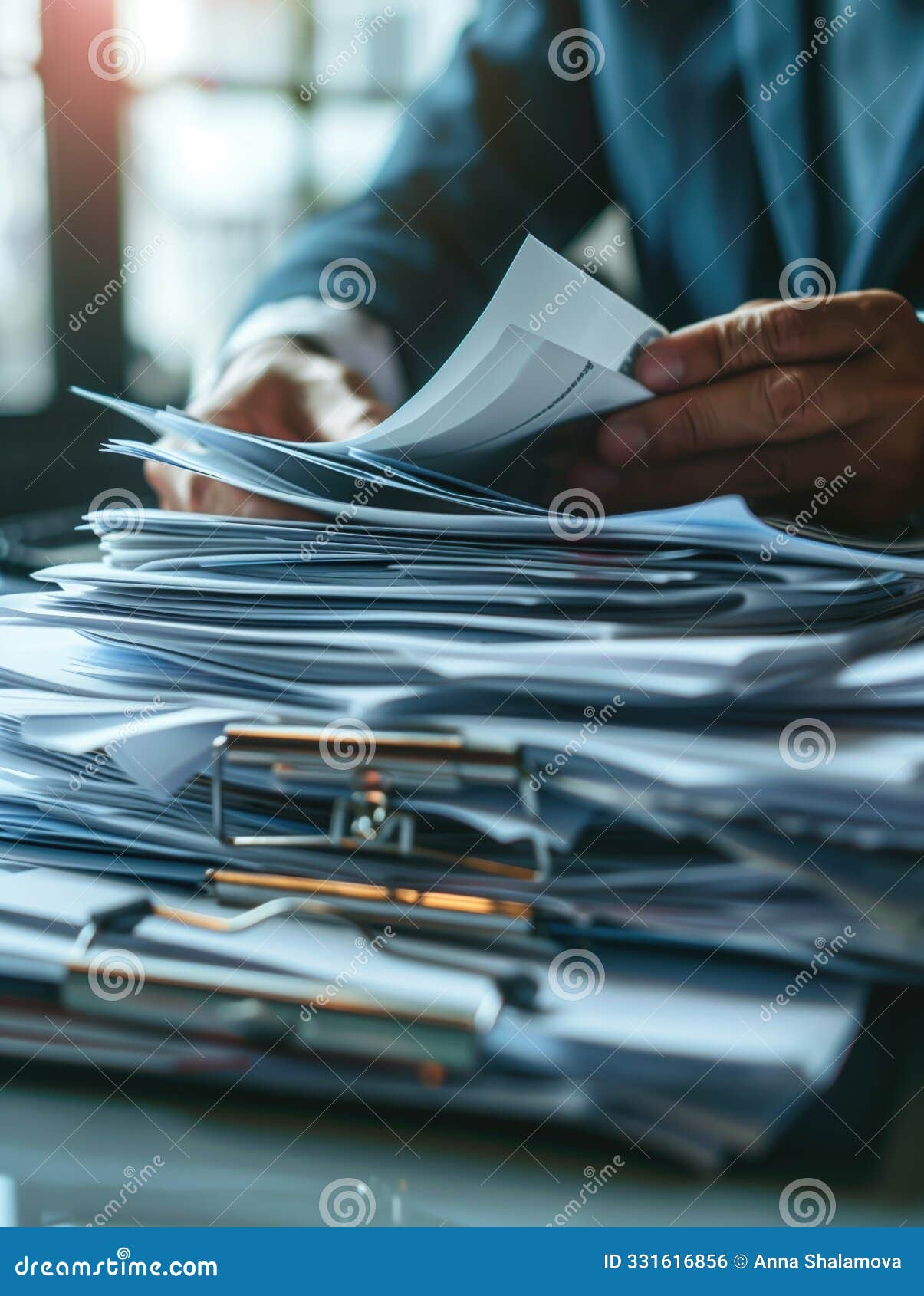 Hands Sorting through a Large Stack of Paperwork on a Desk, with a ...