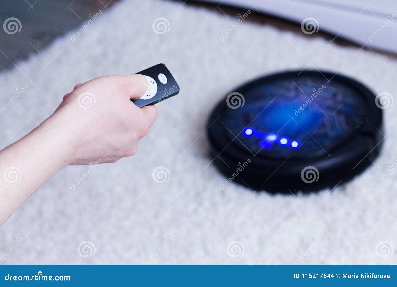 Hands Using Remote Control for a Robot Vacuum Cleaner on a White Stock ...