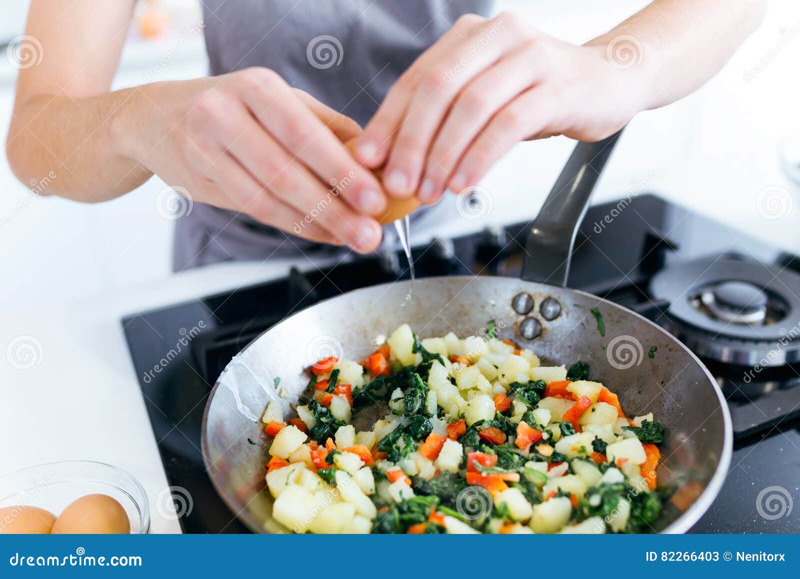 Hands of a Young Woman Adding Egg To Vegetables into the Pan. Stock ...