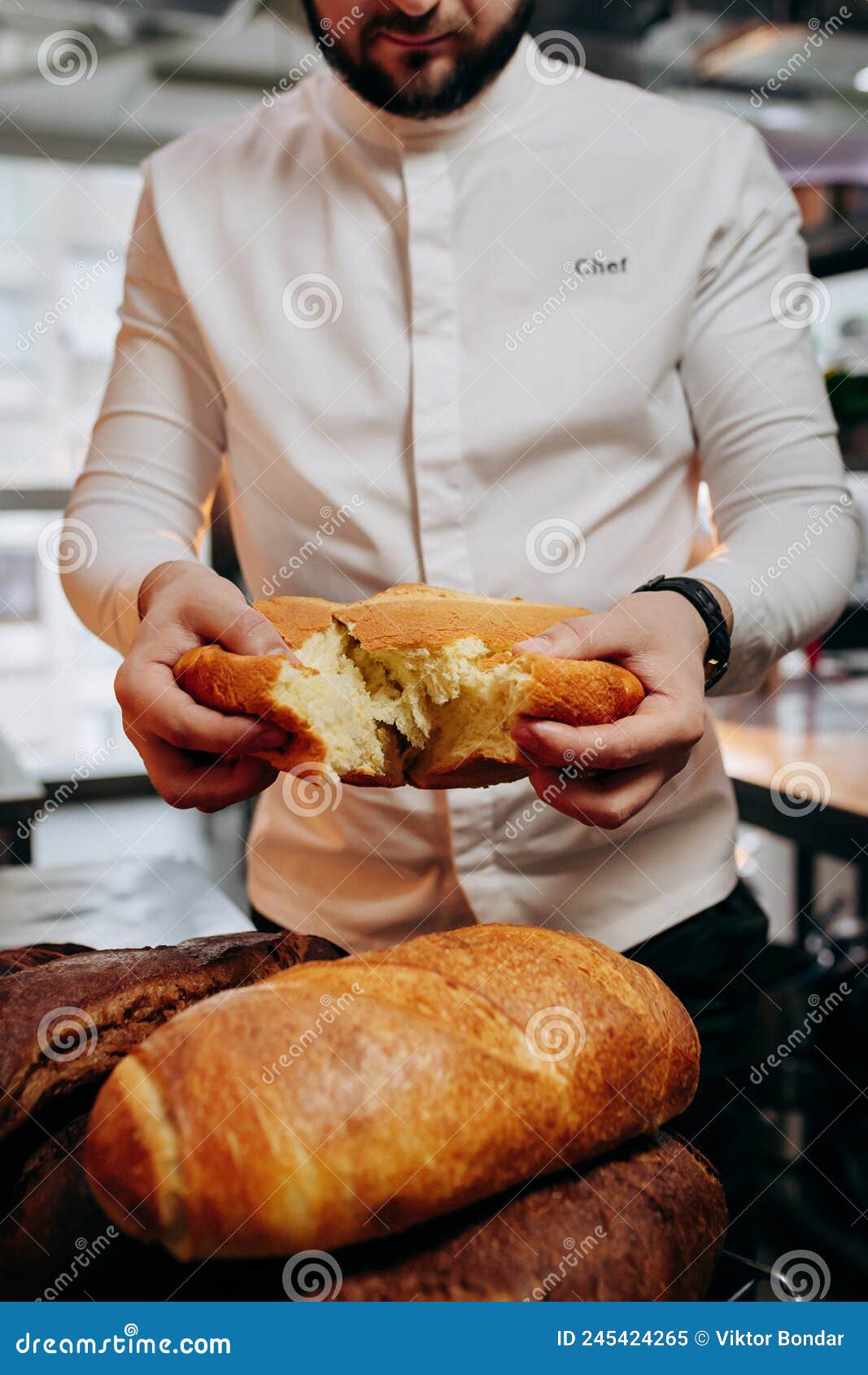 Handsome Baker in Uniform Breaks Freshly Baked Bread at the Bakery ...