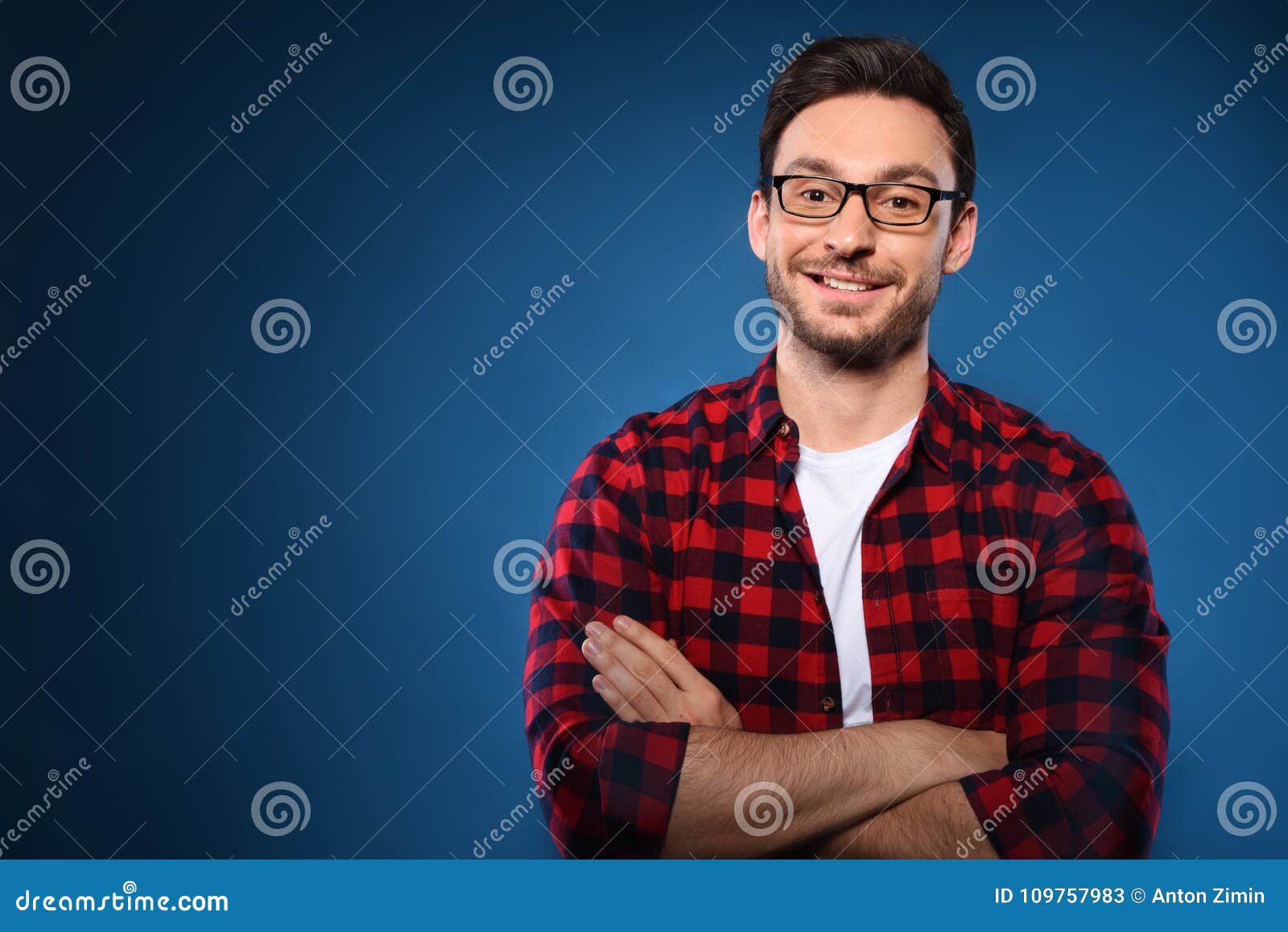 Handsome Bearded Man In Glasses And Red Shirt Isolated On A Dark Blue