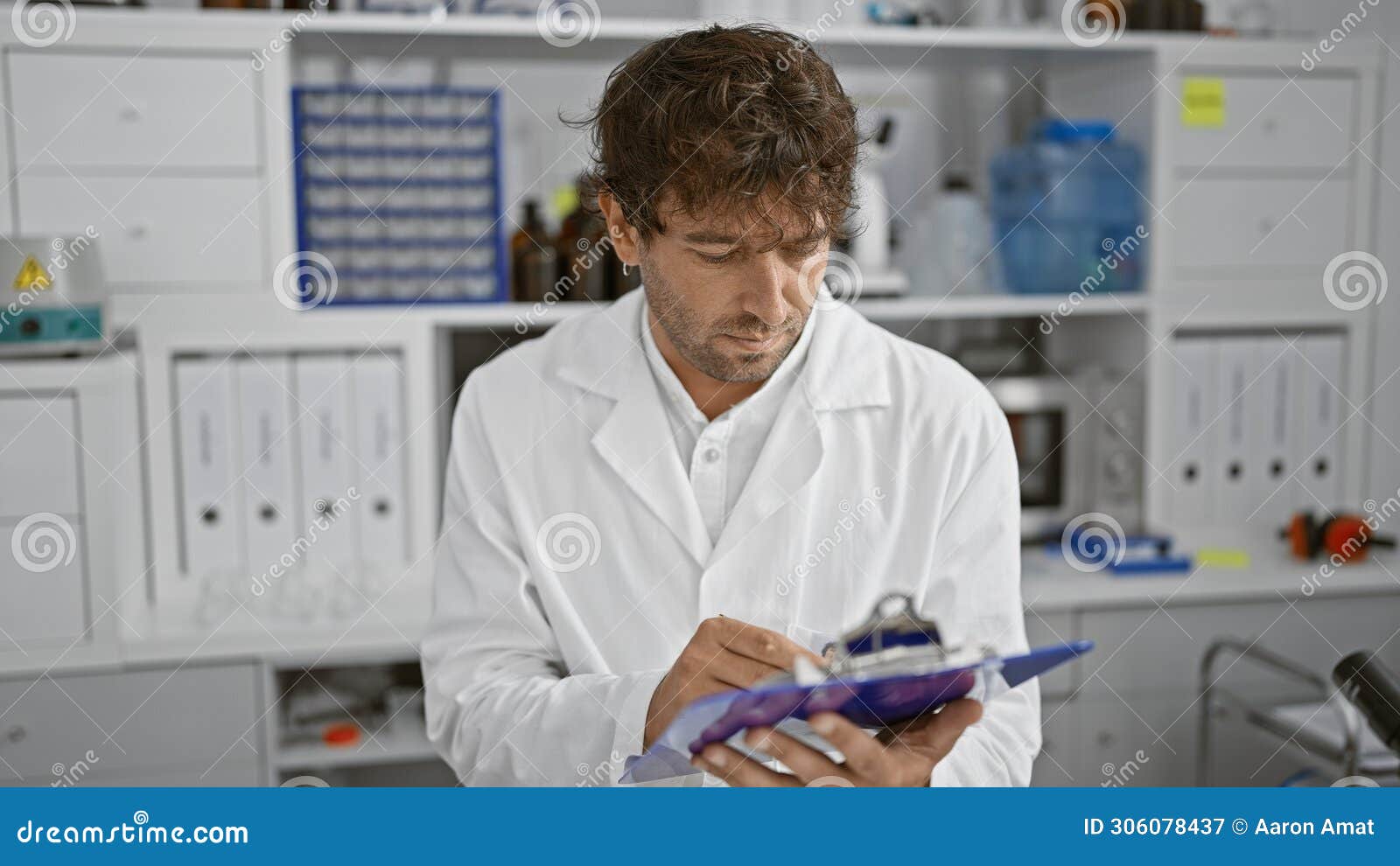 Handsome Bearded Man in Lab Coat Writes on Clipboard in a Modern ...