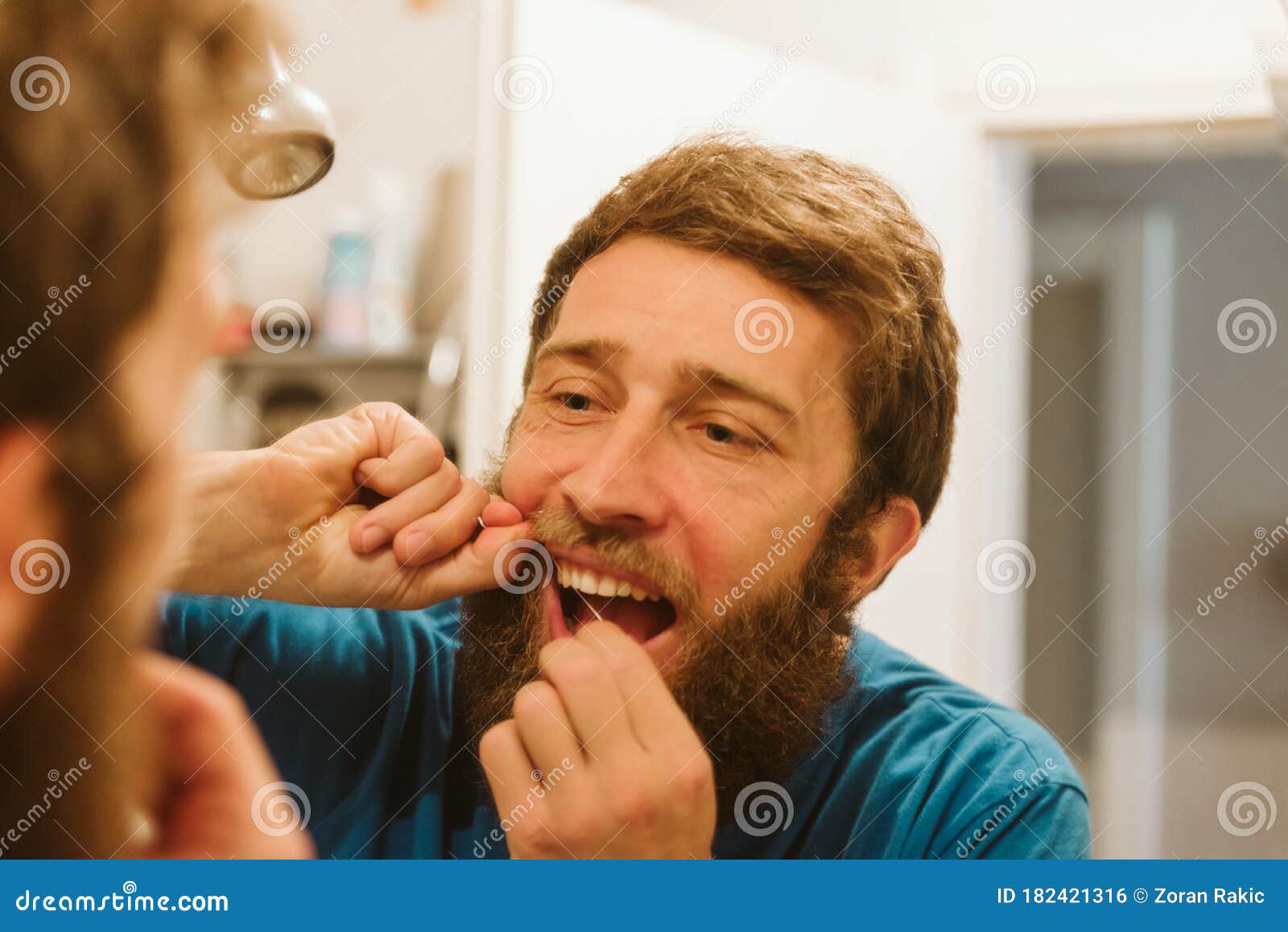Handsome Bearded Man Looking at Mirror while Using Dental Floss in ... Handsome Bearded Man Looking at Mirror while Using Dental Floss in ...