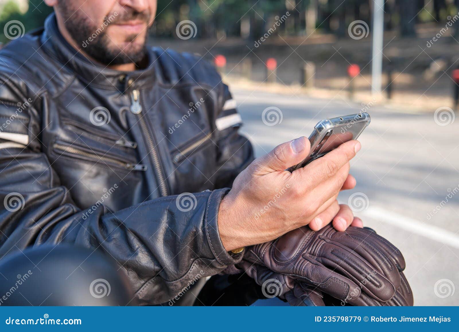 A Handsome Biker Using Mobile Phone on a Rural Road. Stock Image ...