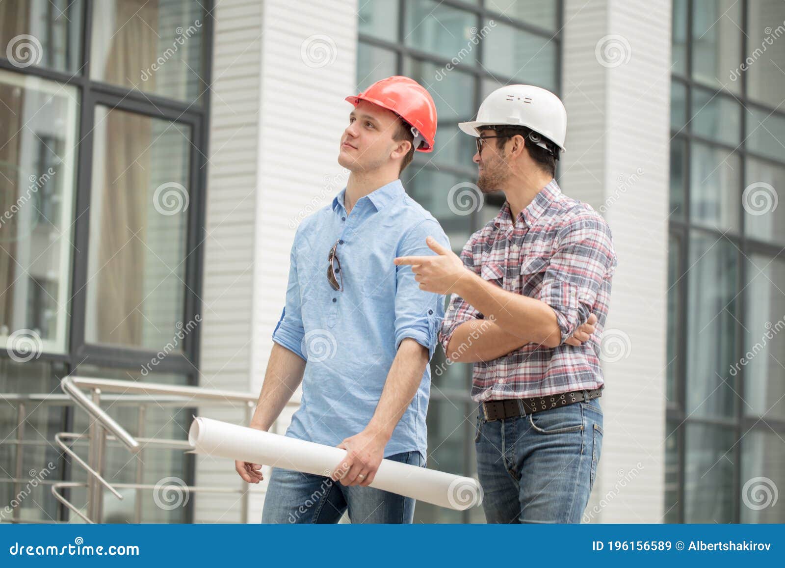 Handsome Builder is Holding Draft while His Colleague Pointing at ...