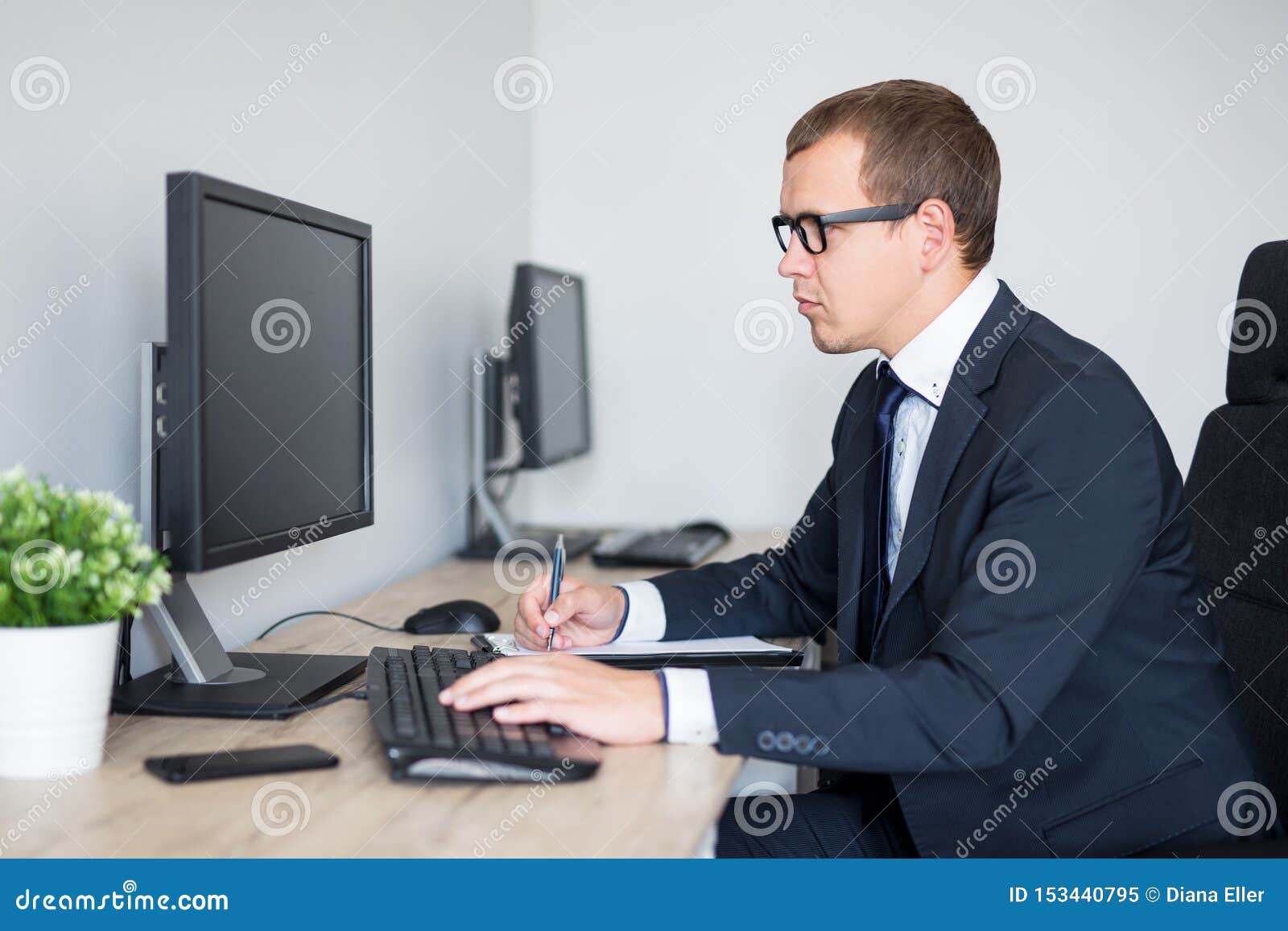 Handsome Businessman Using Computer and Writing Something on Clipboard ...