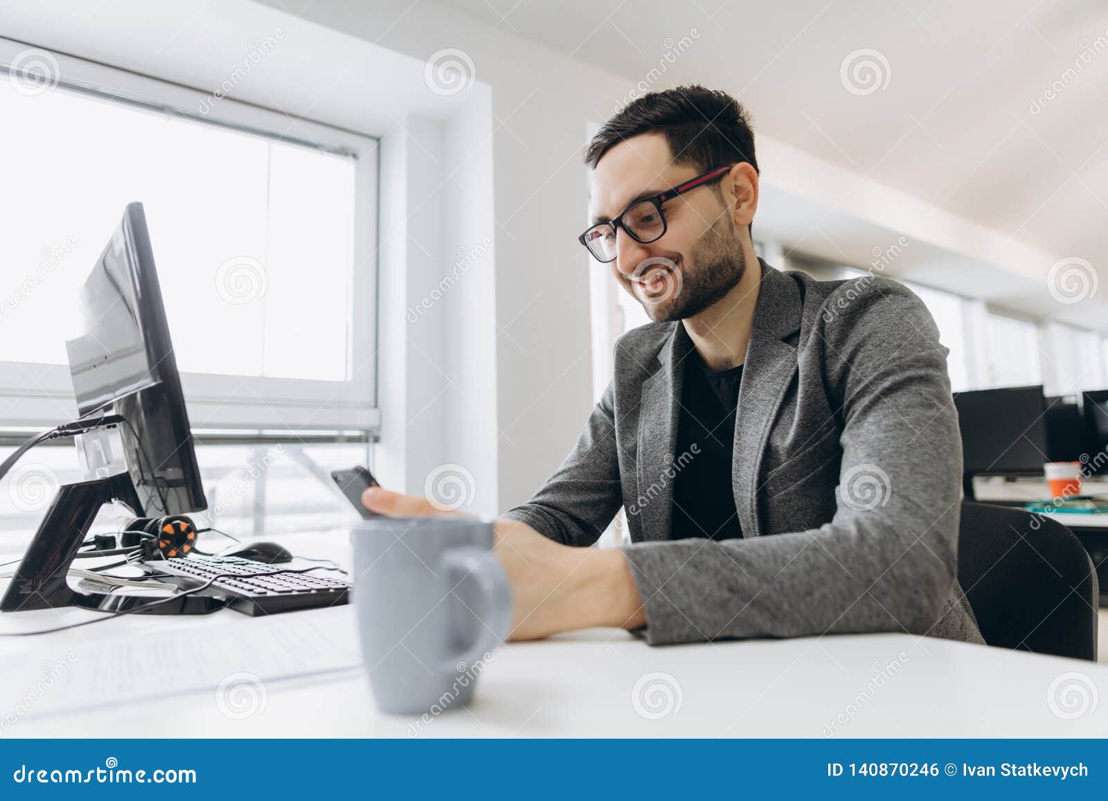 Handsome Businessman is Using a Smartphone and Smiling while Working in ...